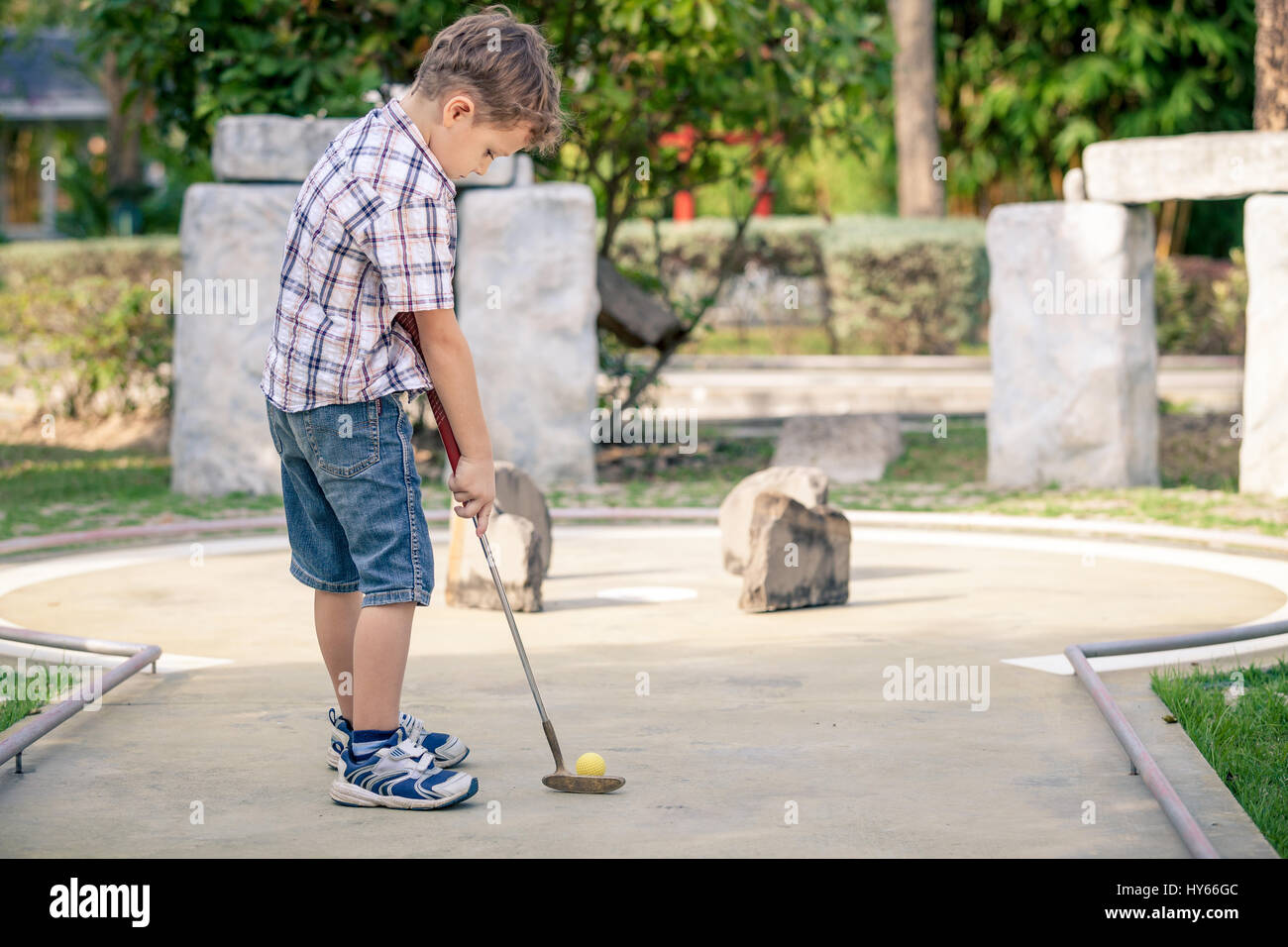 Little boy swinging mini golf club at the day time Stock Photo - Alamy