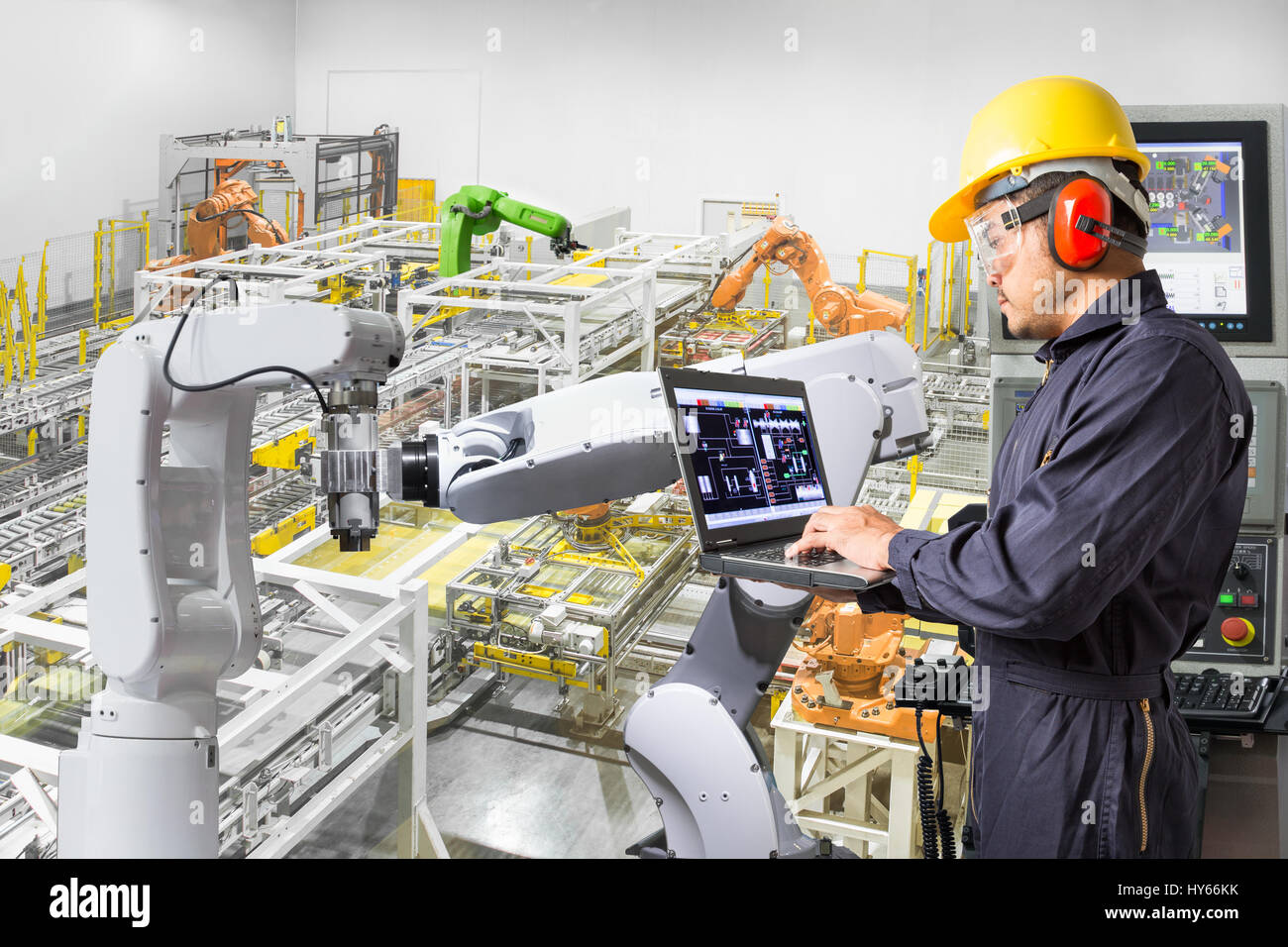 Engineer using laptop computer for maintenance automatic robotic hand machine tool at industrial ...