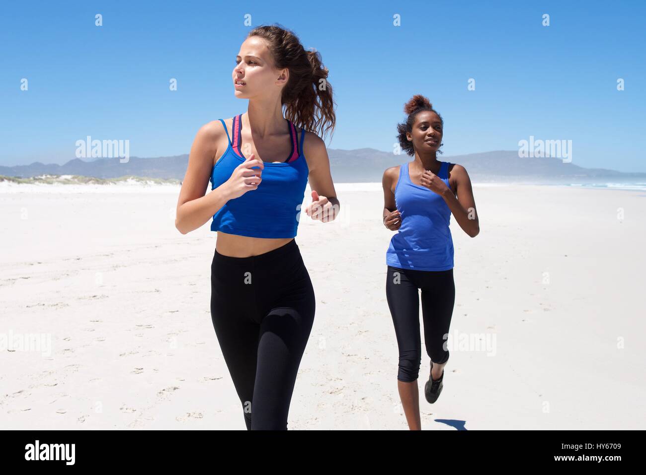 Portrait of young woman running with her friend in the background on ...