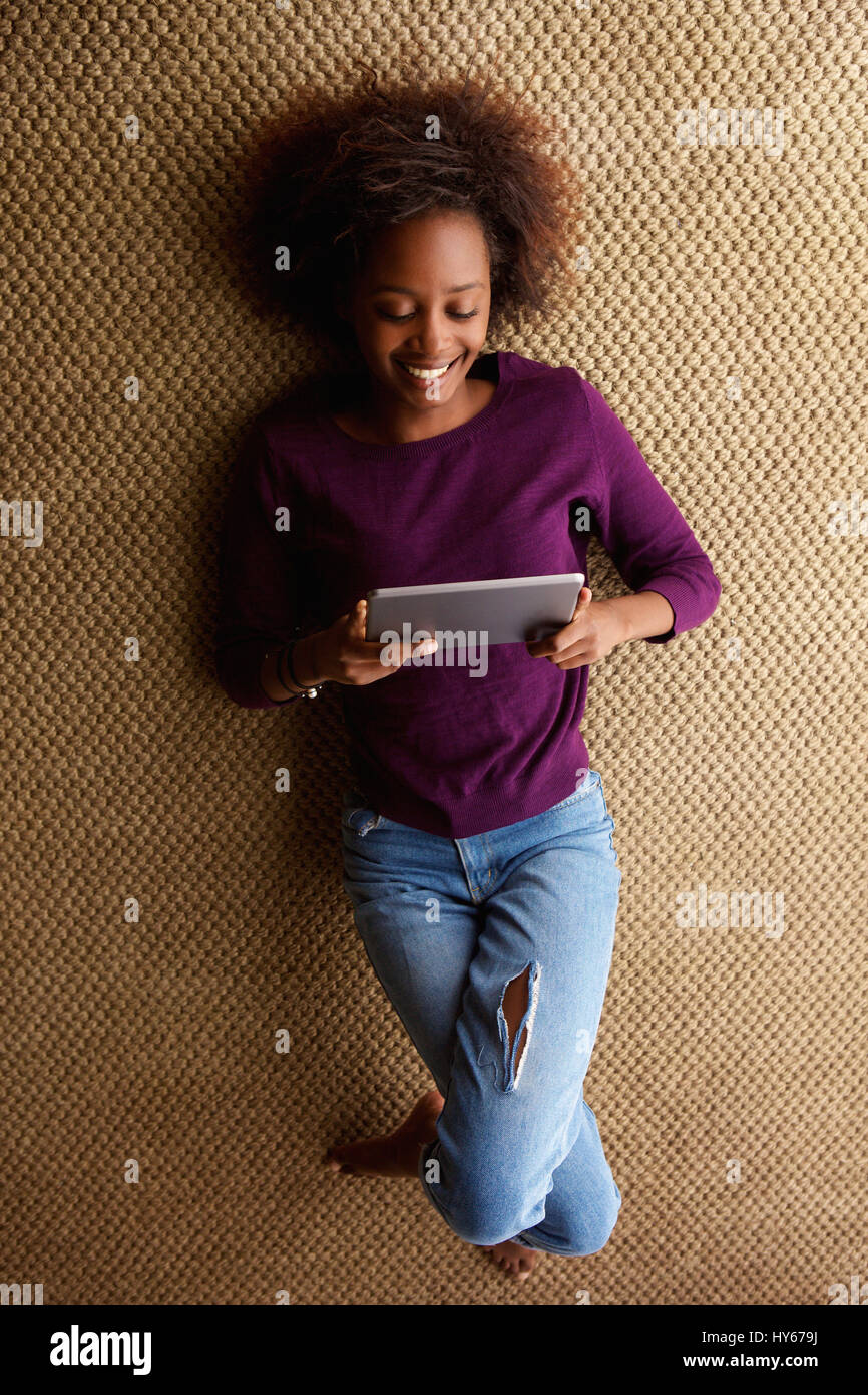 Portrait from above young black woman lying down with digital tablet ...