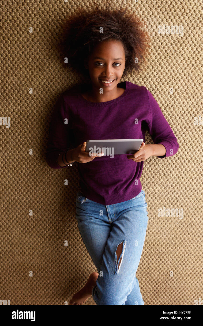Portrait from above young african woman lying down with digital tablet ...