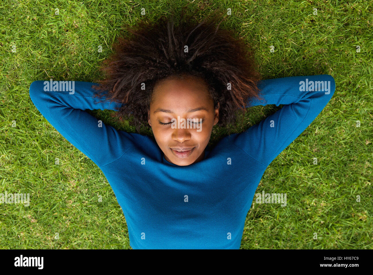 Portrait from above of a young african woman lying on grass sleeping ...