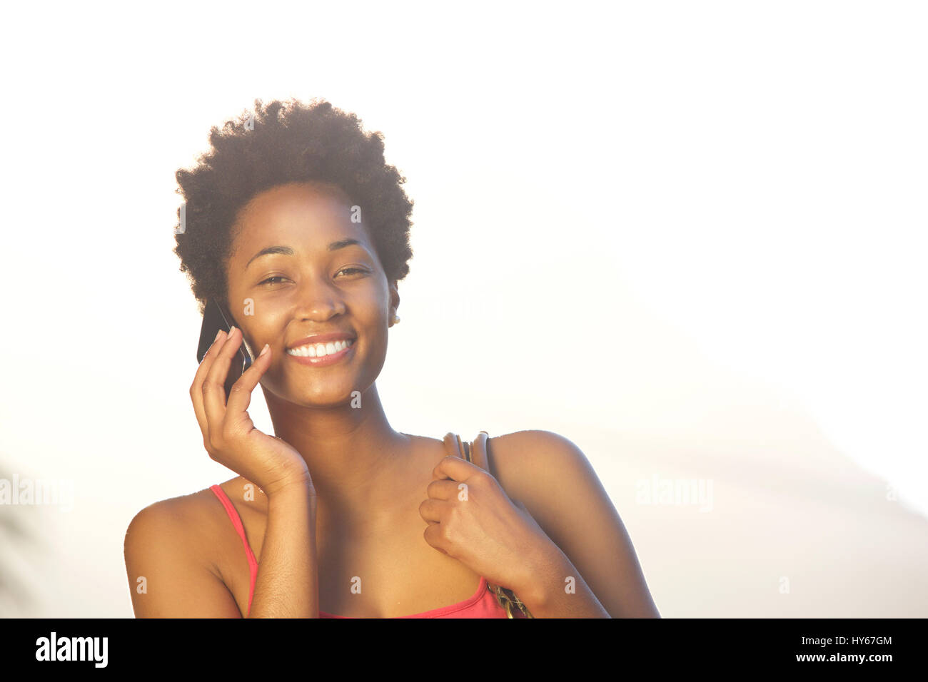 Close up portrait of a beautiful young african woman talking on mobile ...
