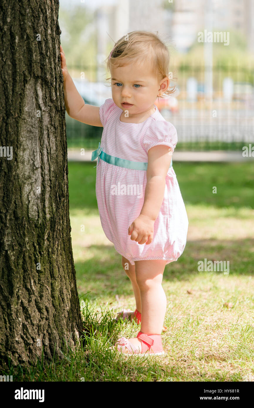 Beautiful baby girl touching a tree Stock Photo - Alamy