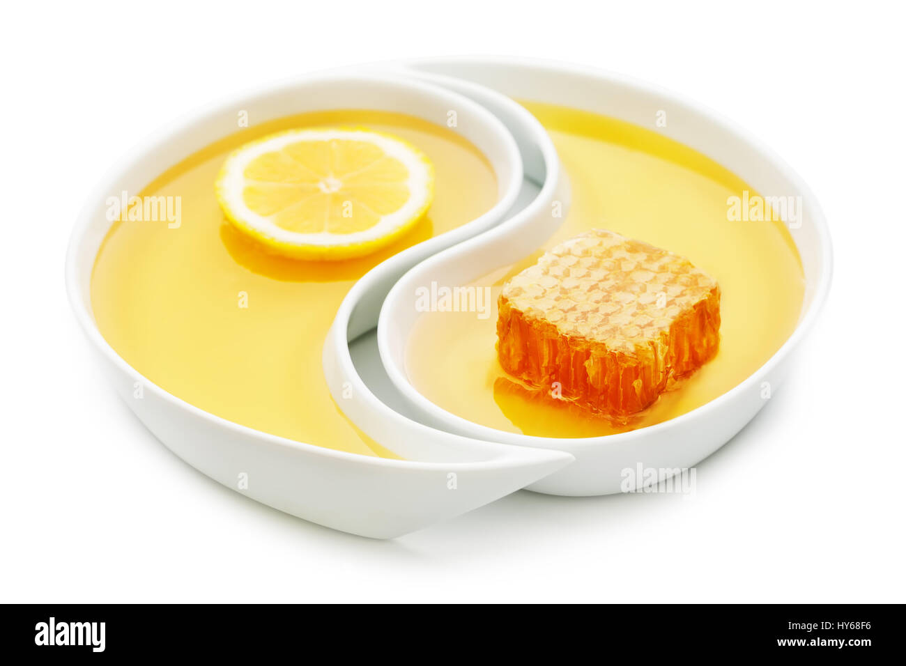 Honey, a honeycomb and a slice of lemon in two yin yang trays, isolated ...