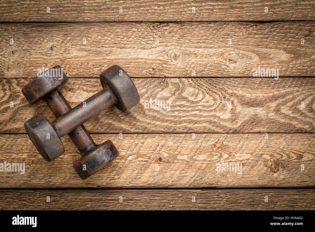 a pair of vintage iron rusty dumbbells on a grained barn wood ...