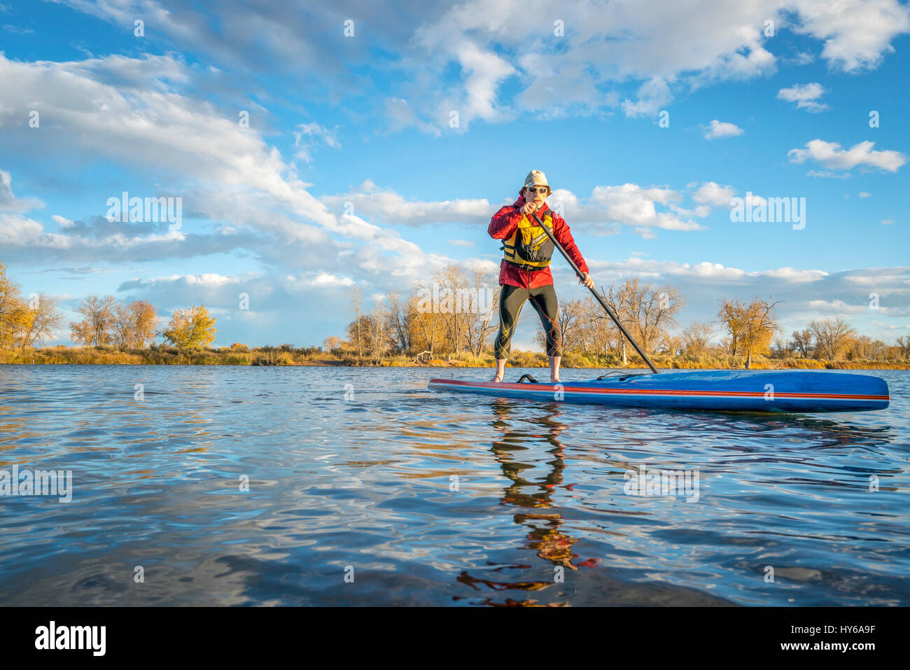 paddling stand up paddleboard on a lake in Colorado, fall scenery with ...