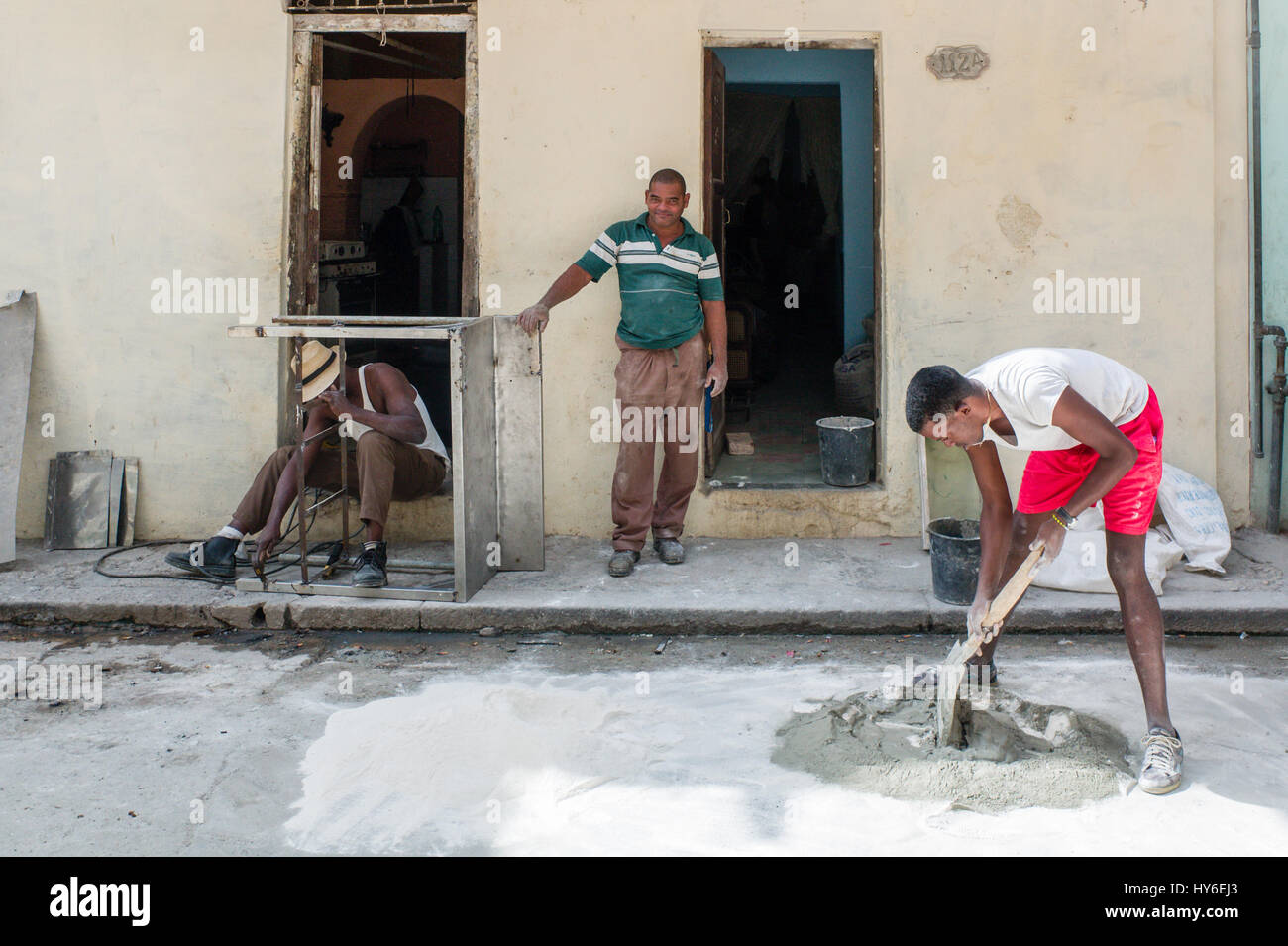 Construction workers mixing cement in the middle of the street in old ...