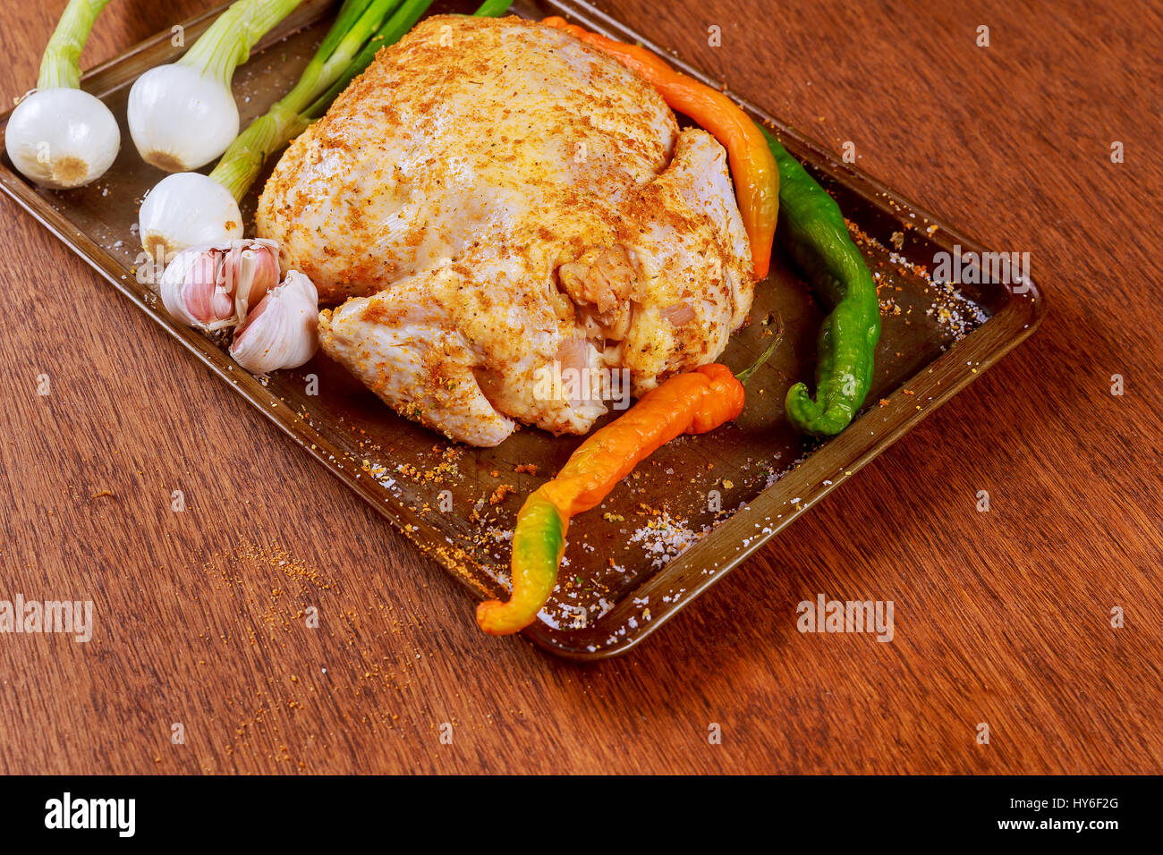Uncooked whole chicken in baking form with chopped vegetables carrots ...