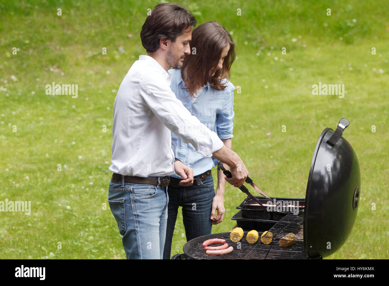 Happy couple cooking food on barbecue Stock Photo - Alamy