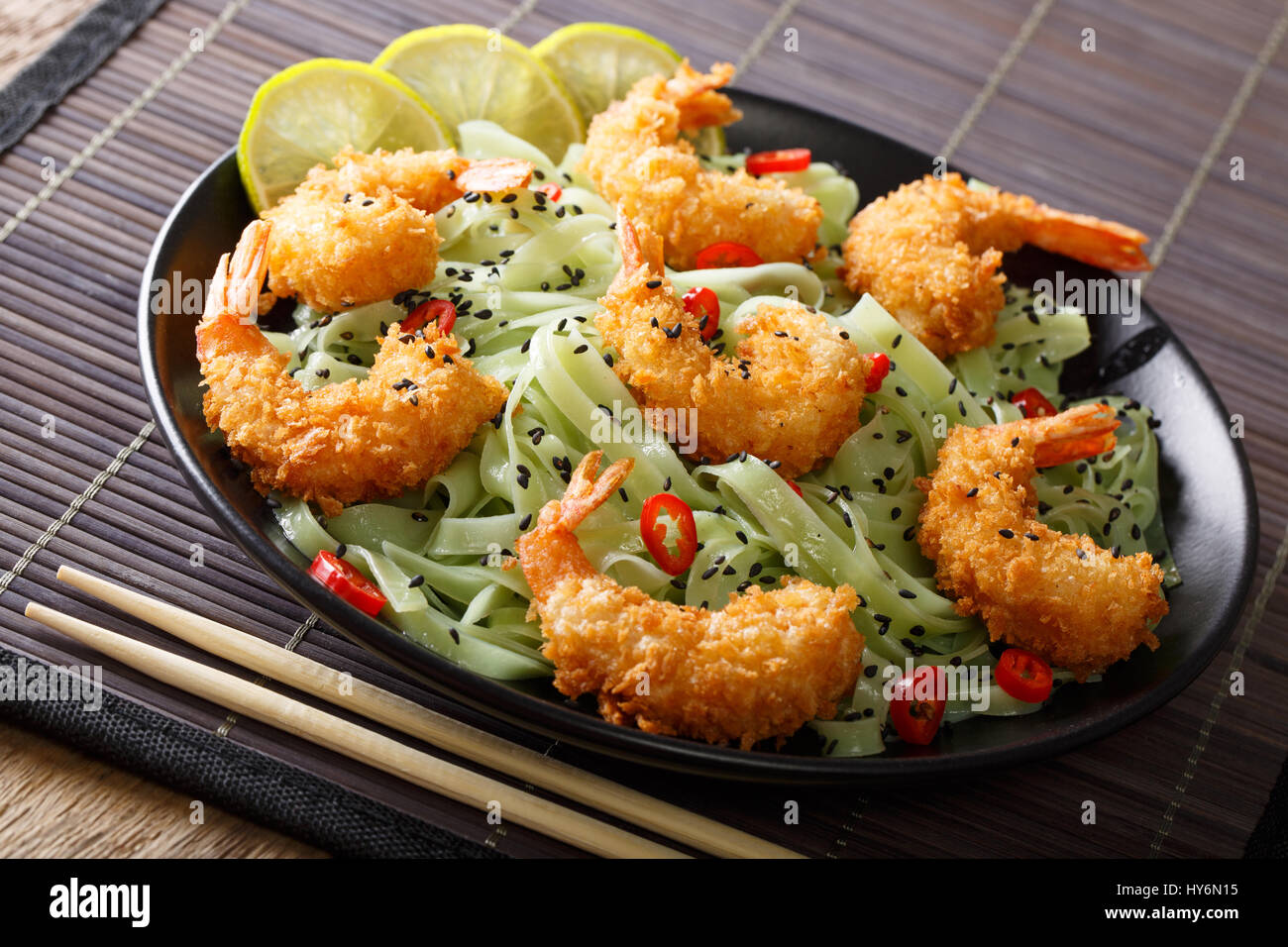 Shrimp tempura with green tea pasta, chili pepper and sesame close-up ...