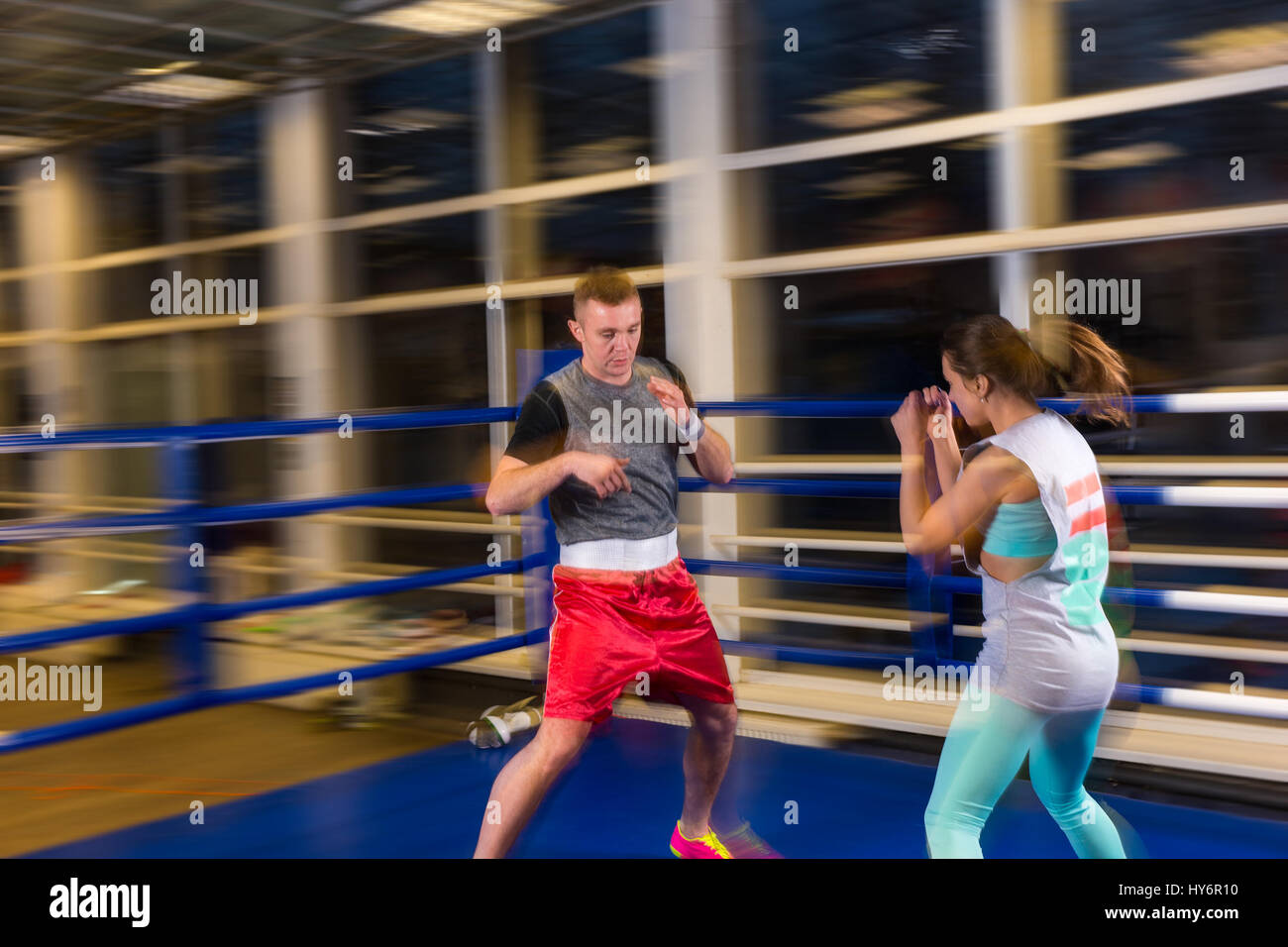 Male and female in action practicing boxing in a boxing ring in a gym ...