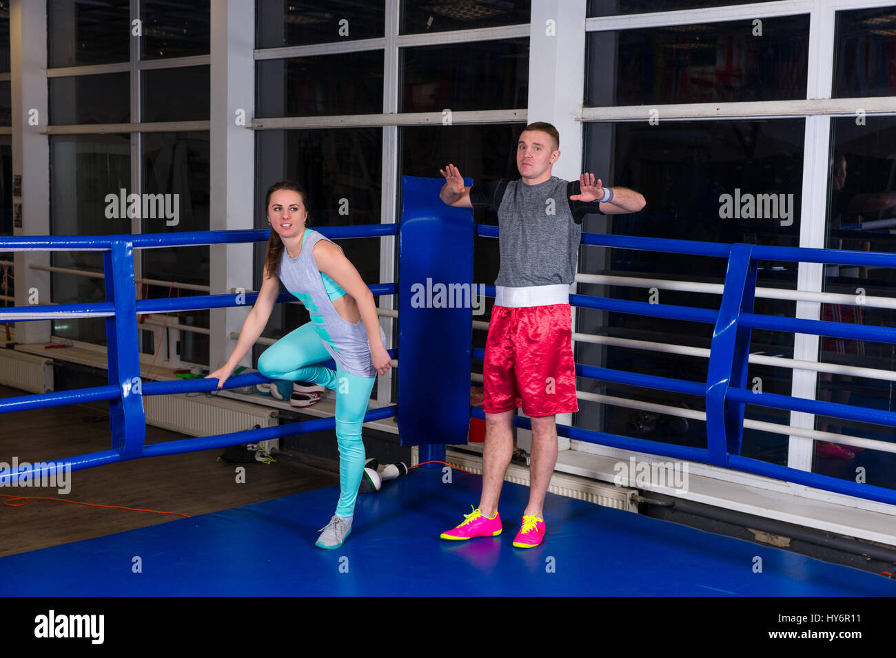 Sporty couple standing near blue corner of a regular boxing ring ...