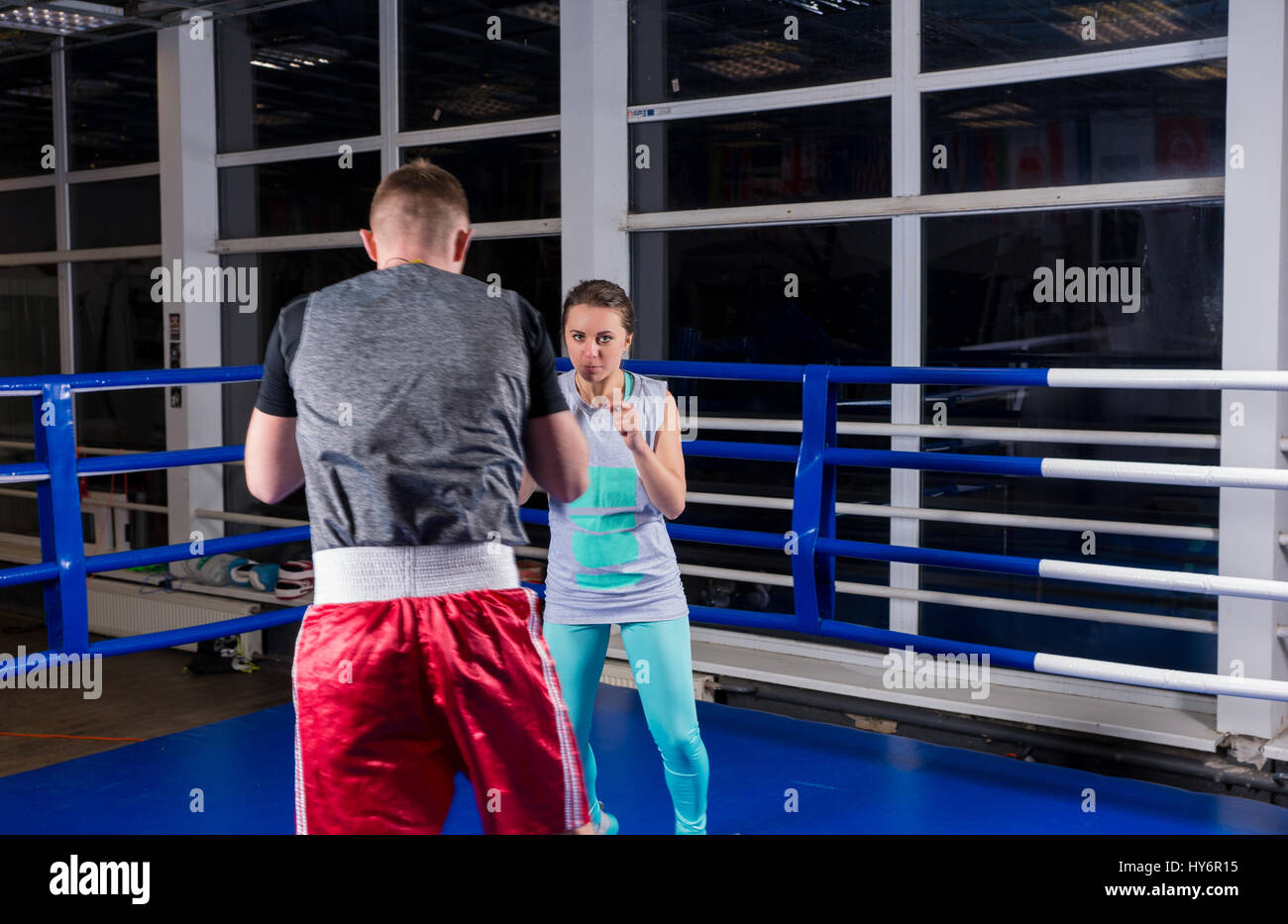 Sporty pair in action practicing boxing in regular boxing ring in a gym ...