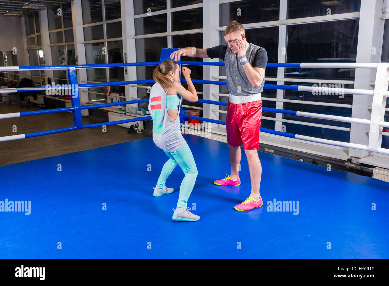 Athletic young couple in sportswear practicing boxing in regular boxing ...