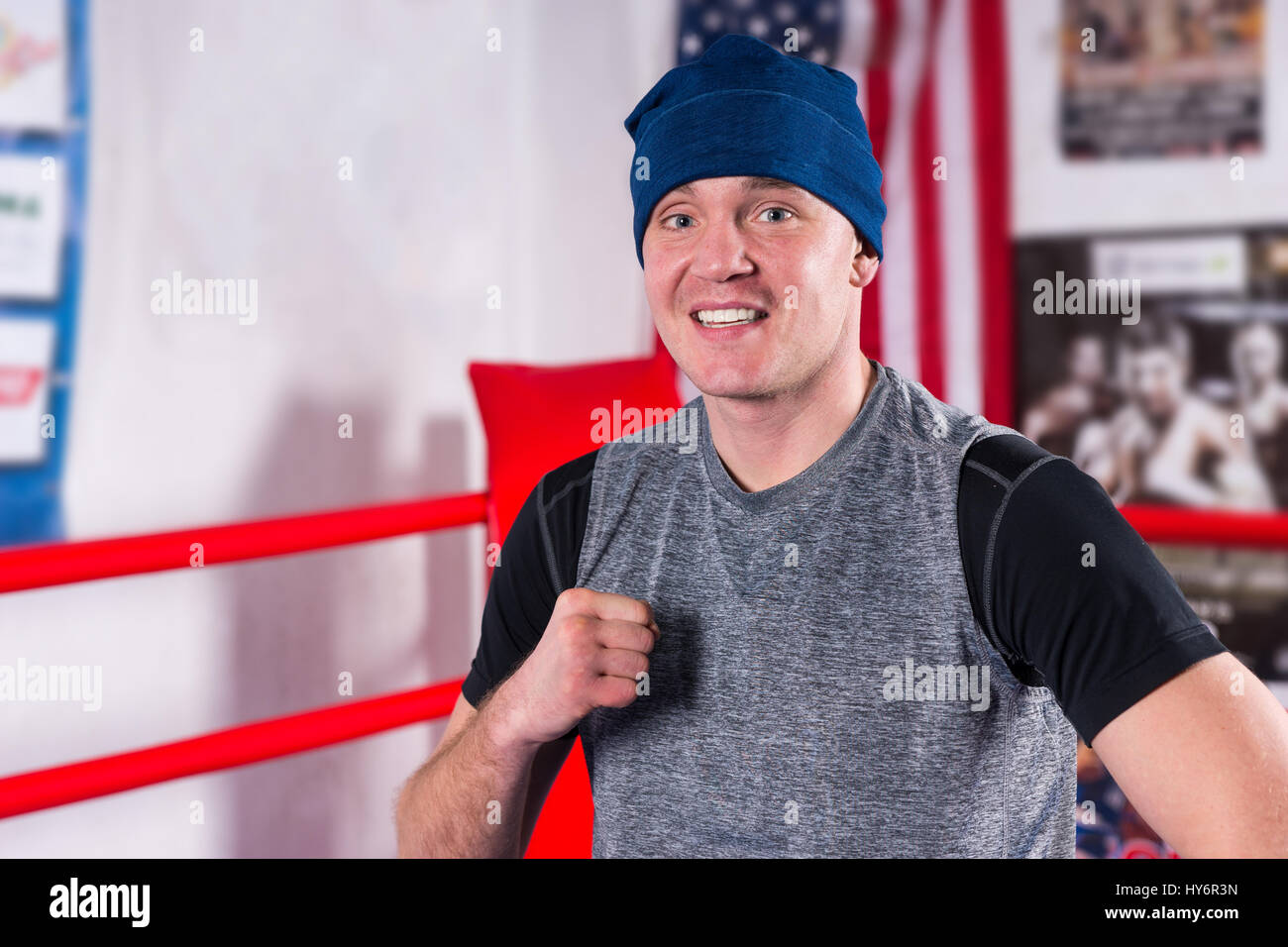 Smiling male boxer standing in a regular boxing ring surrounded by ...
