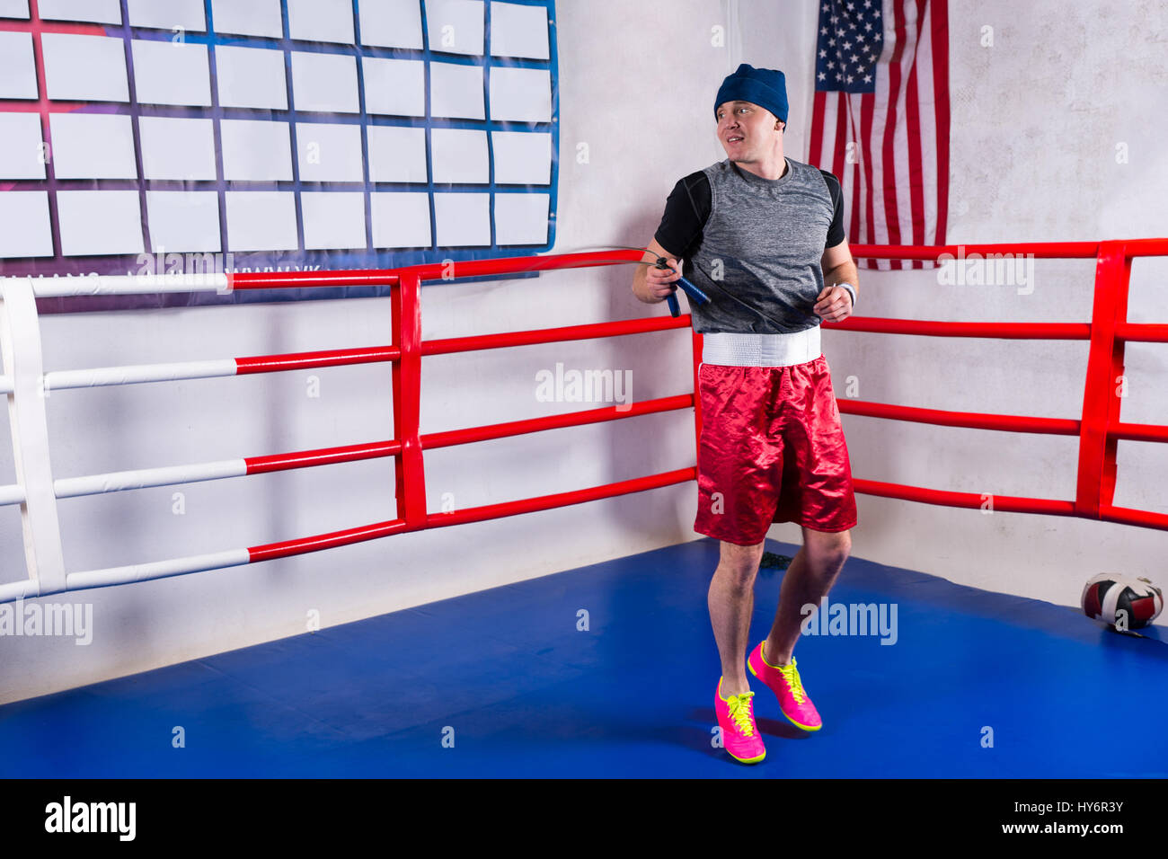 Male boxer exercising with jumping rope in a regular boxing ring ...