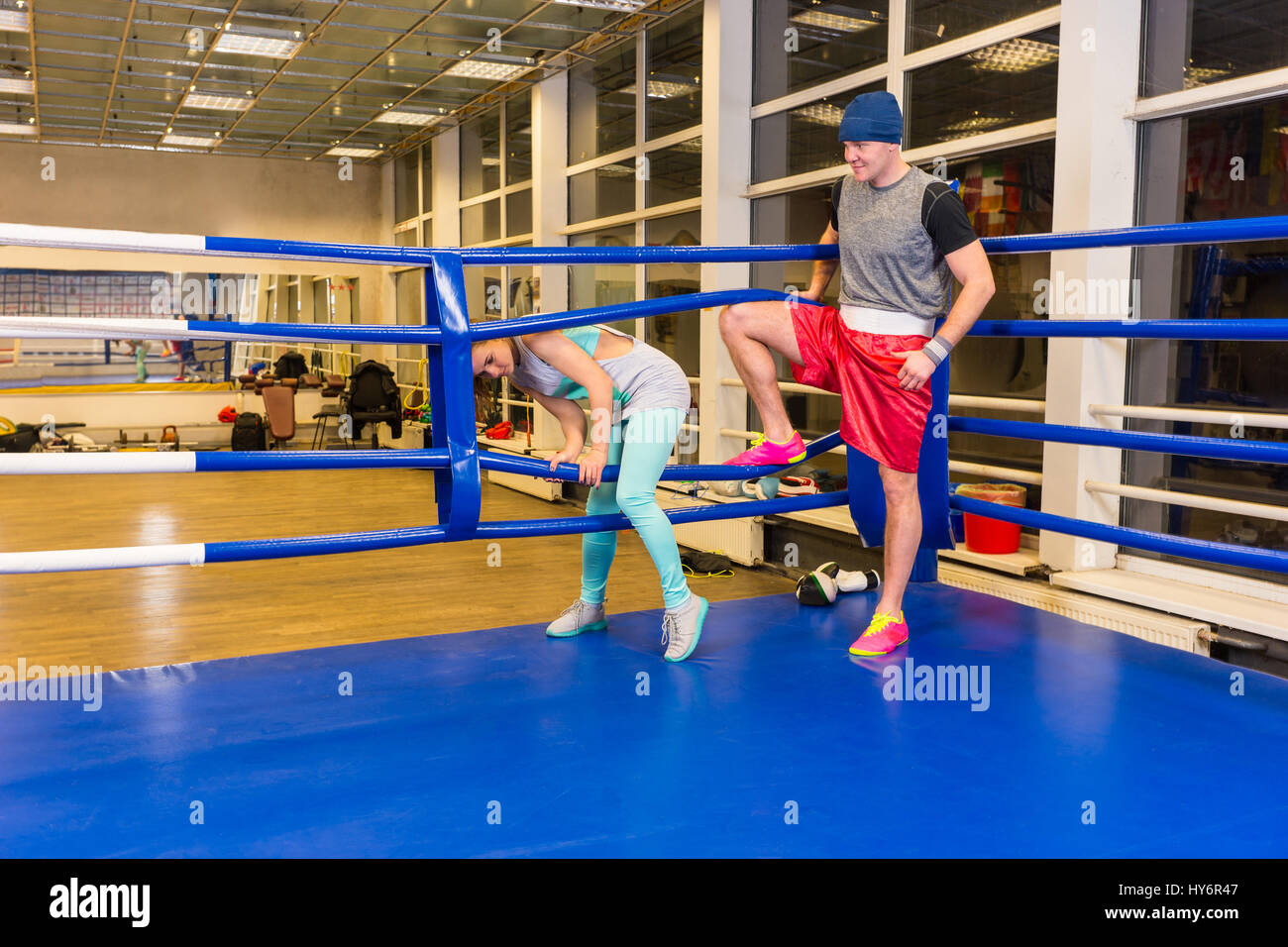 Sporty woman coming in regular boxing ring surrounded by ropes in a gym ...