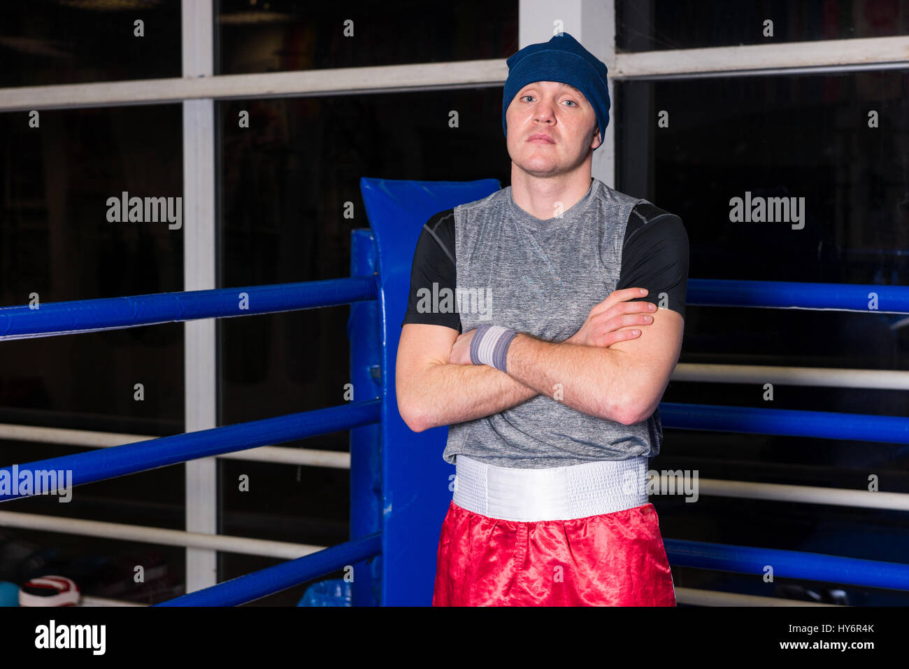 Athletic boxer with arms across standing in a regular boxing ring ...