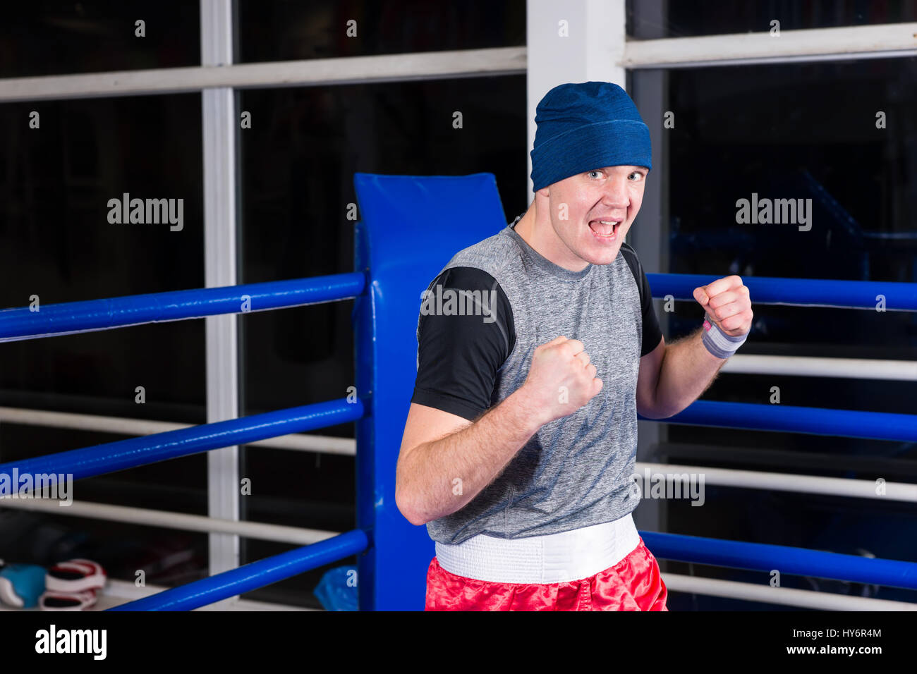 Athletic young boxer standing in a pose clenching his fists in a ...