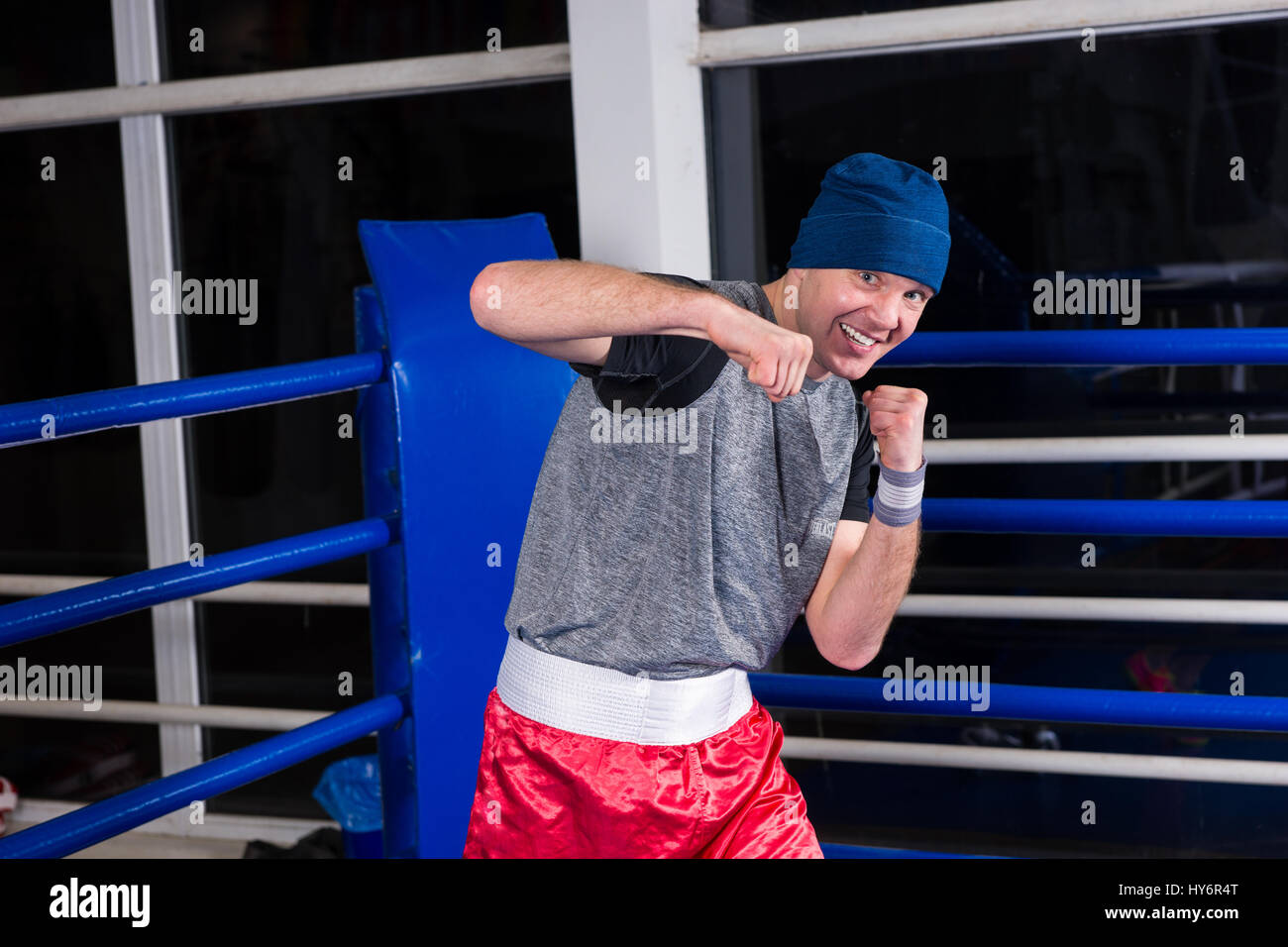 Athletic young male boxer standing in a pose clenching his fists in a ...