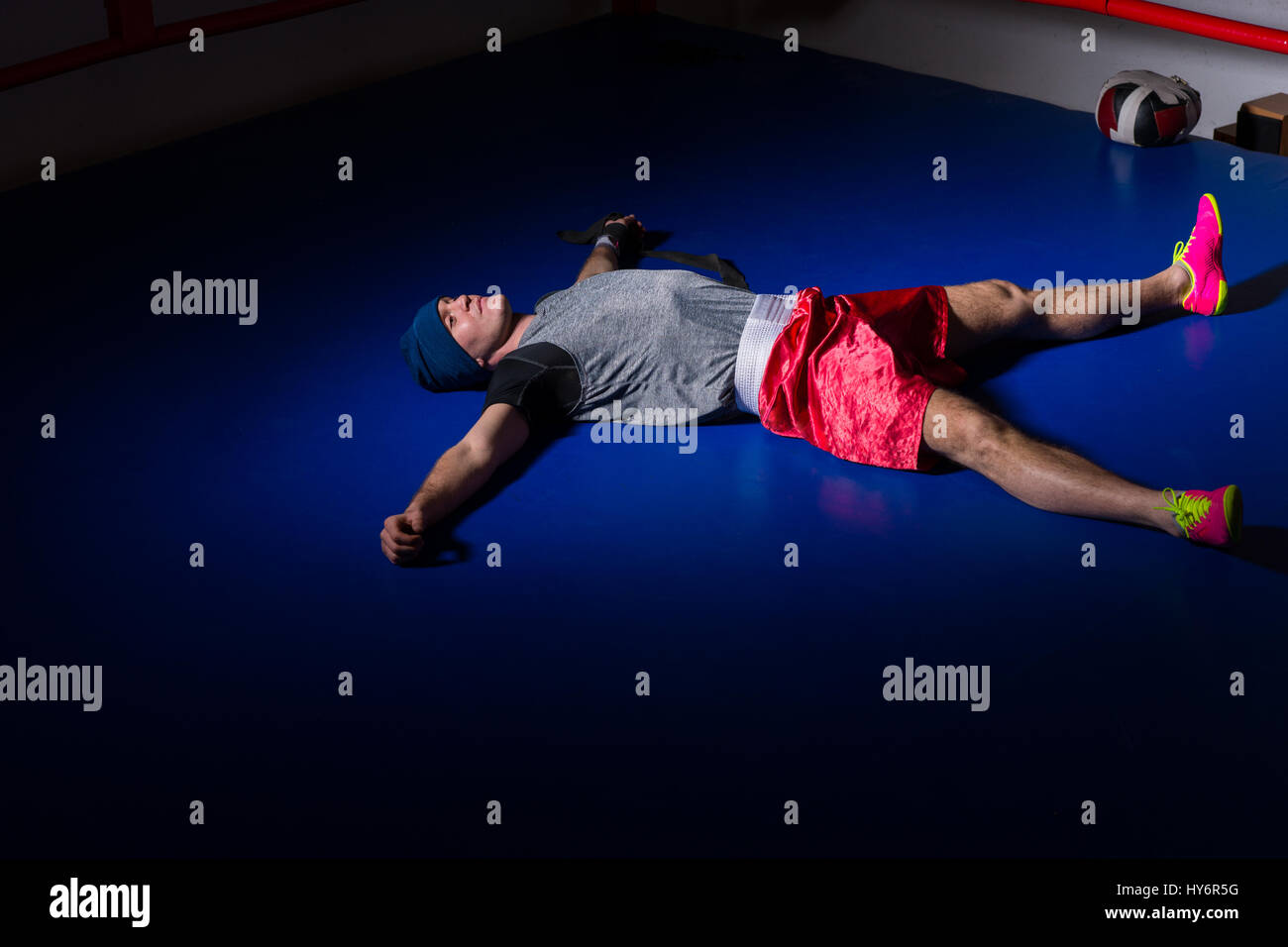 Young sporty boxer in sportswear lying and resting after workout in ...