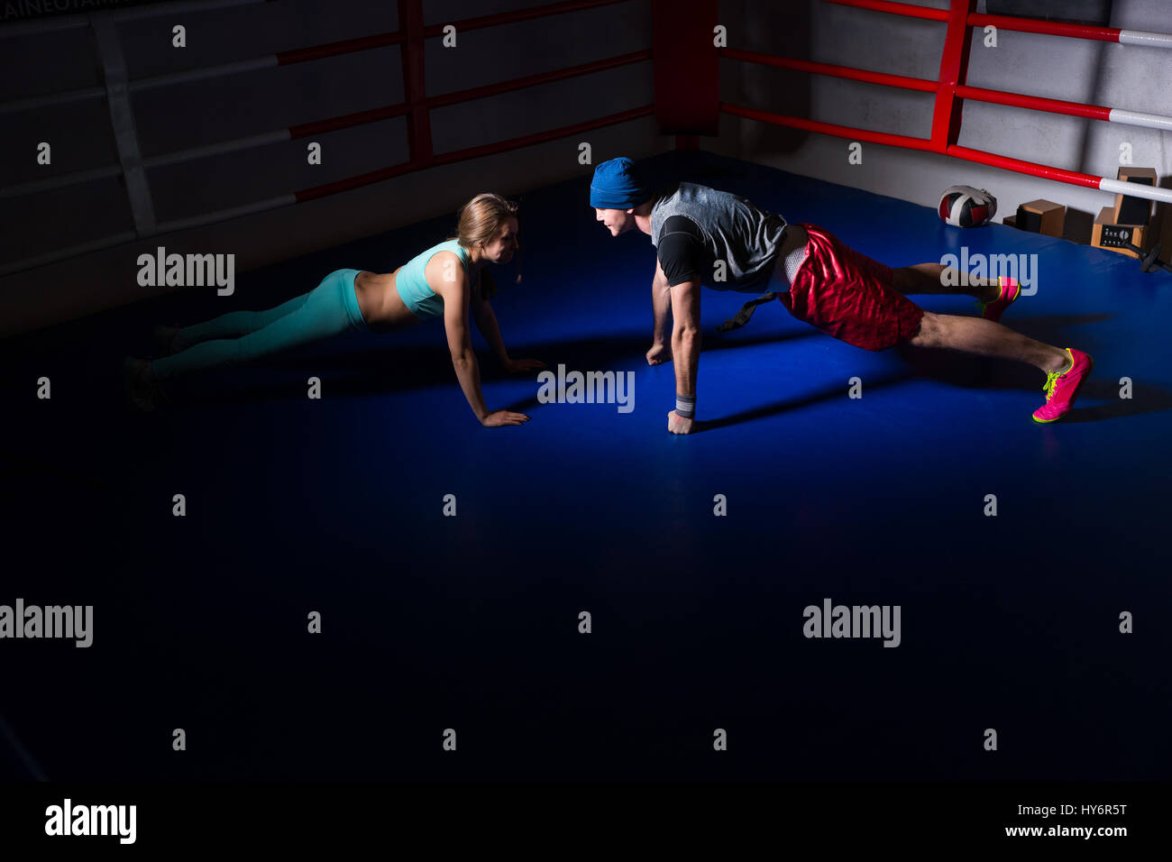 Sporty boxing couple in sportswear doing push-up in regular boxing ring ...