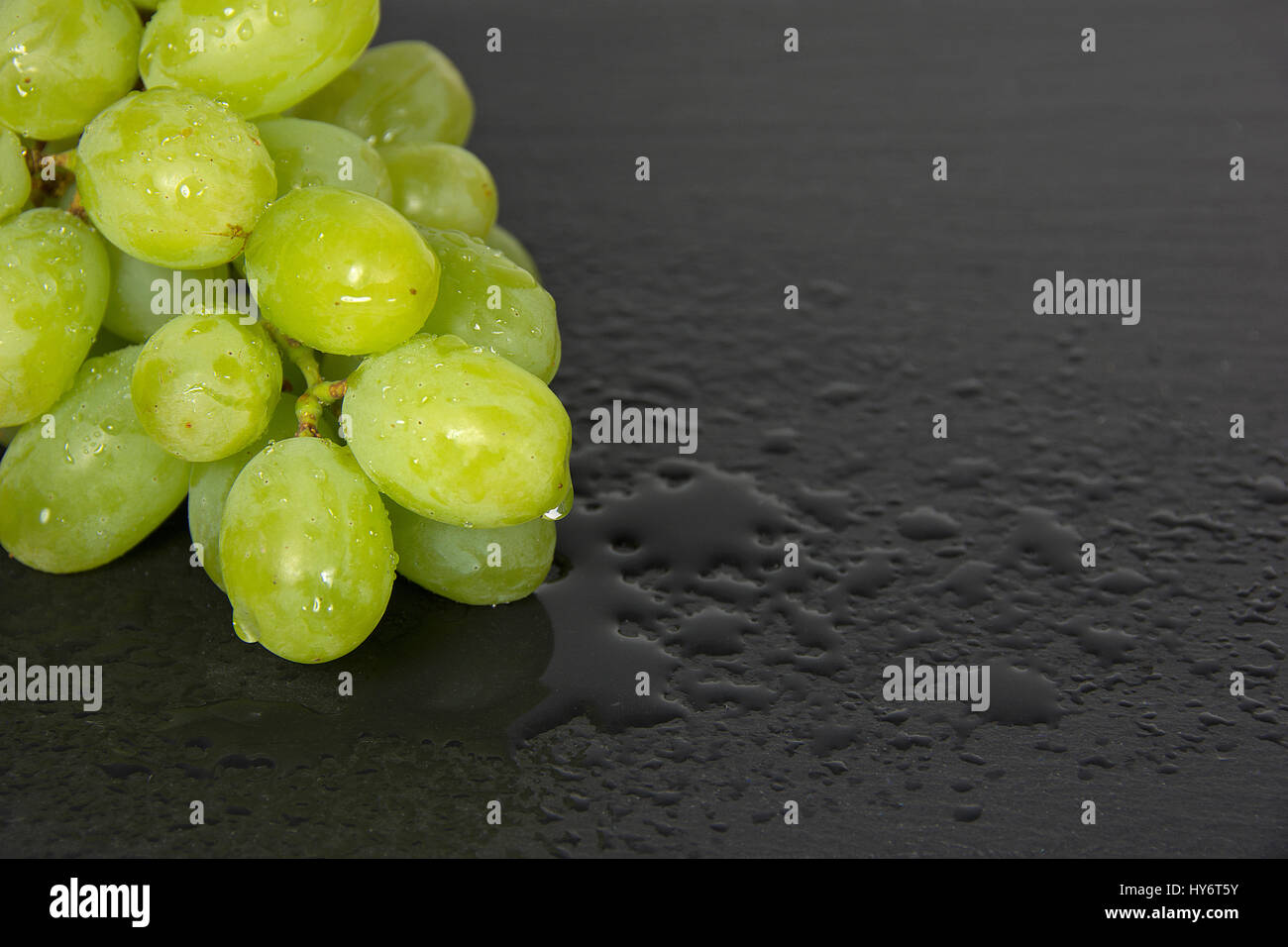 close up of wet green grapes on black slate Stock Photo - Alamy