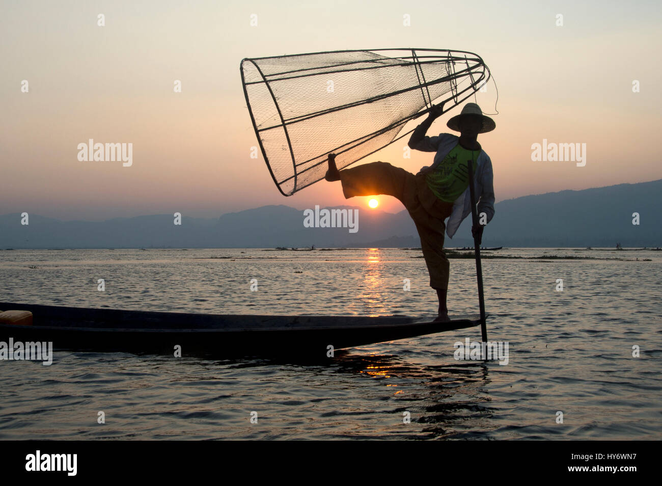 Myanmar (Burma). Inle lake. A fisherman poses at sunset with his ...