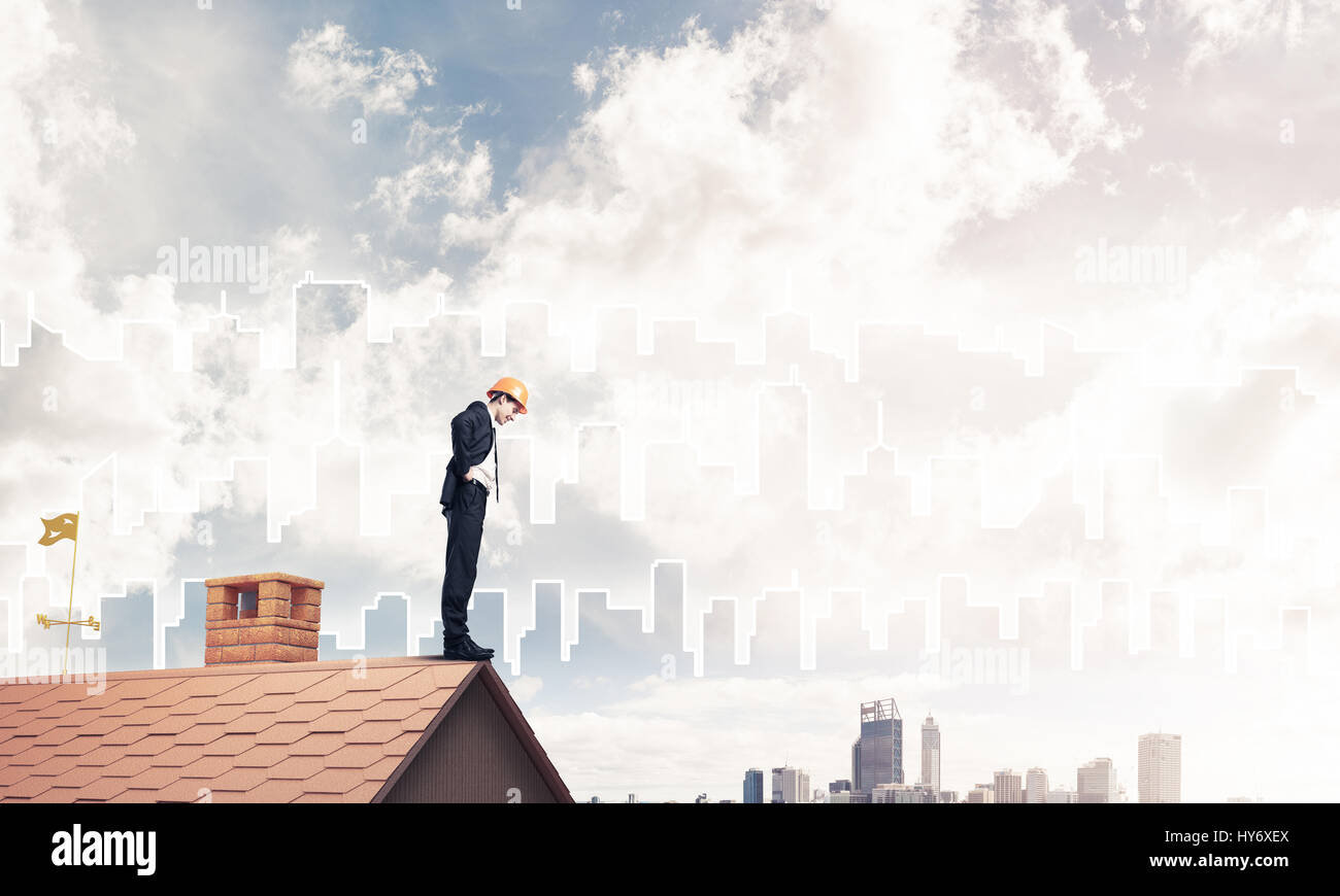 Engineer man standing on roof and looking down. Mixed media Stock Photo ...