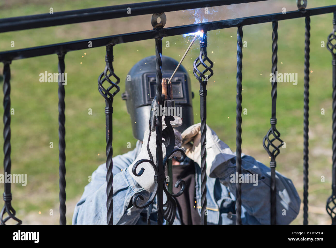 A worker welding metal handrails on the stairs. Wrought iron railings ...