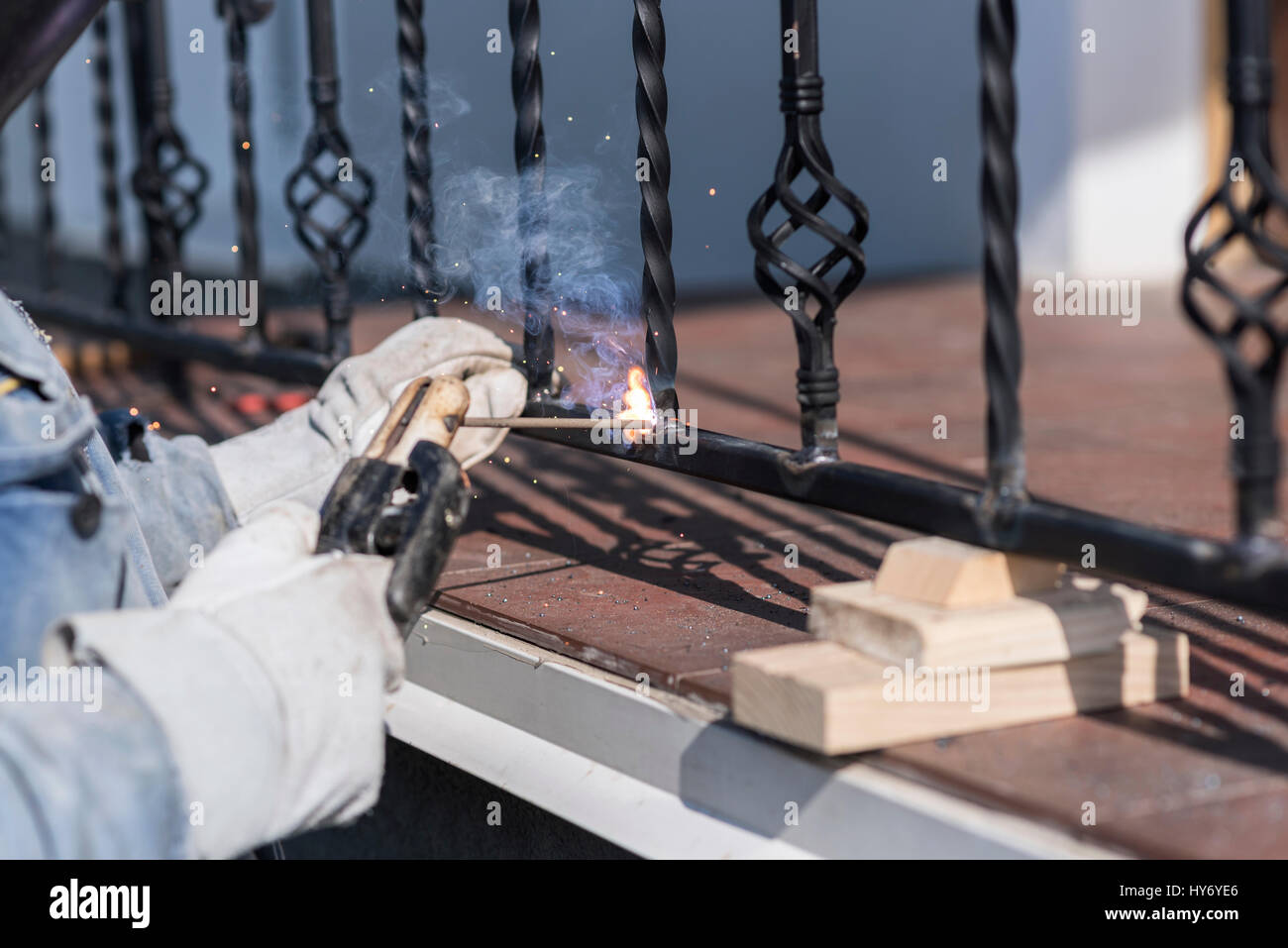 A worker welding metal handrails on the stairs. Wrought iron railings ...