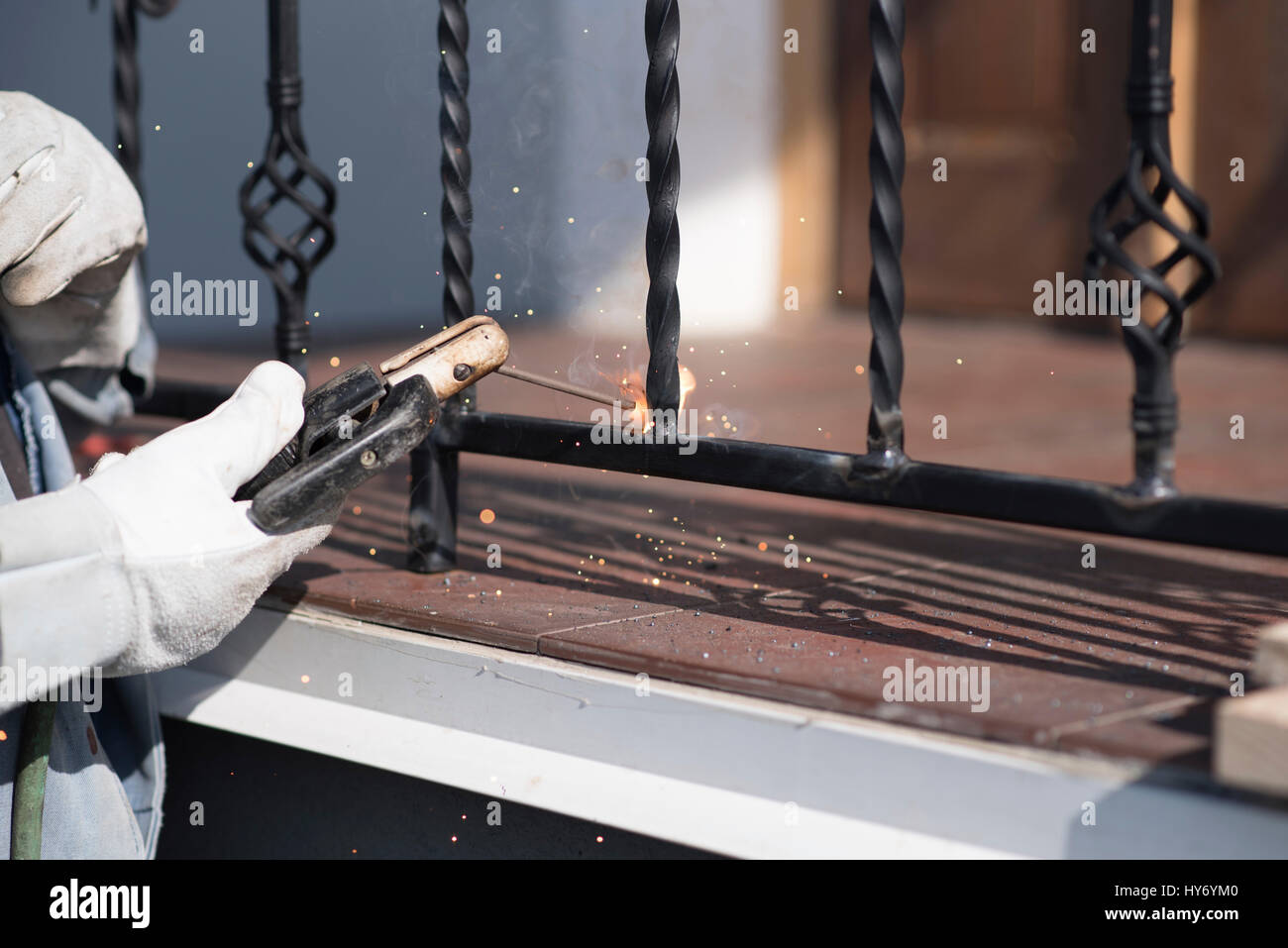 A worker welding metal handrails on the stairs. Wrought iron railings ...