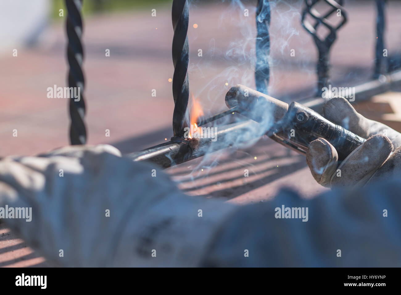 A worker welding metal handrails on the stairs. Wrought iron railings ...