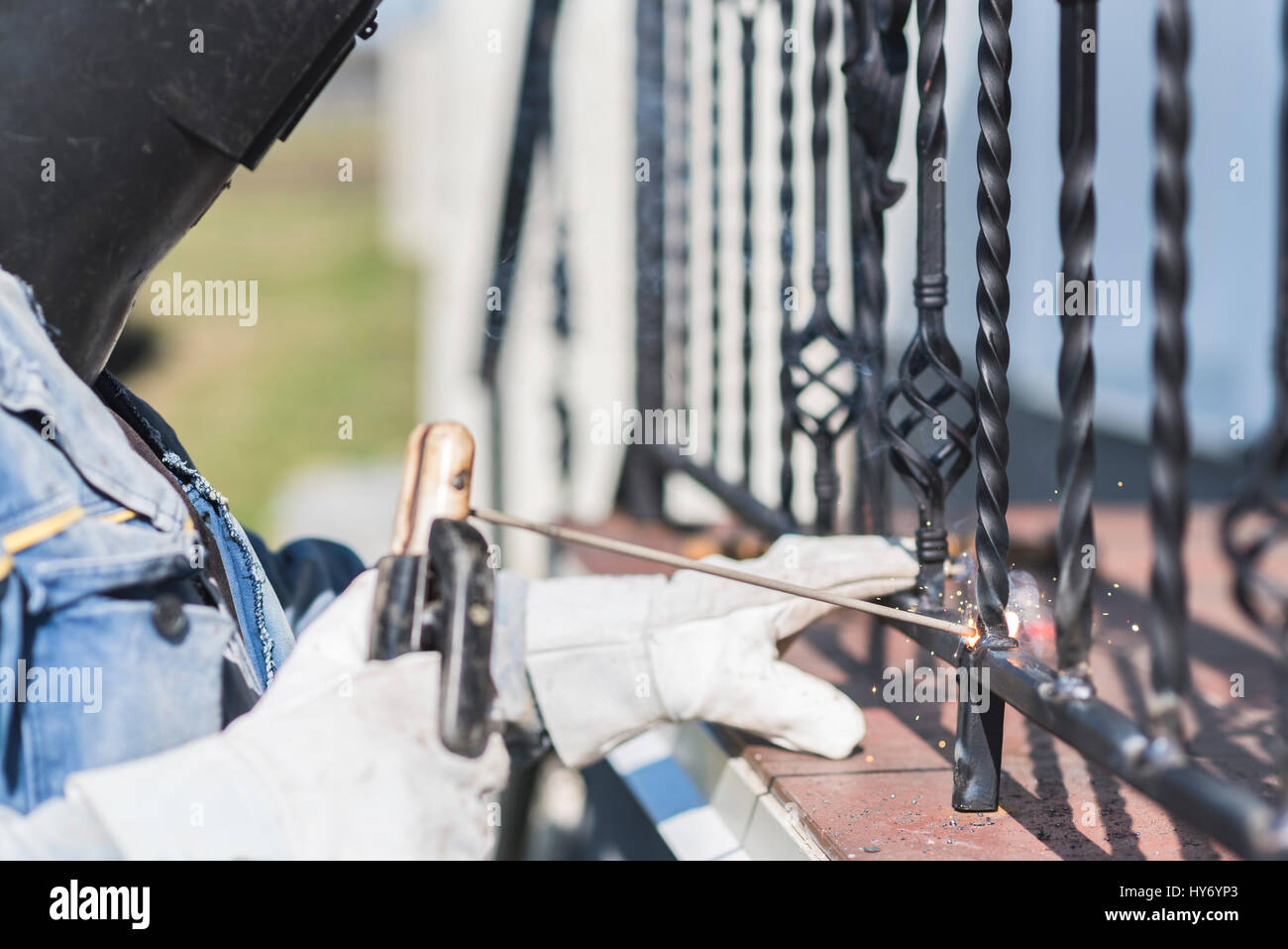 A worker welding metal handrails on the stairs. Wrought iron railings ...