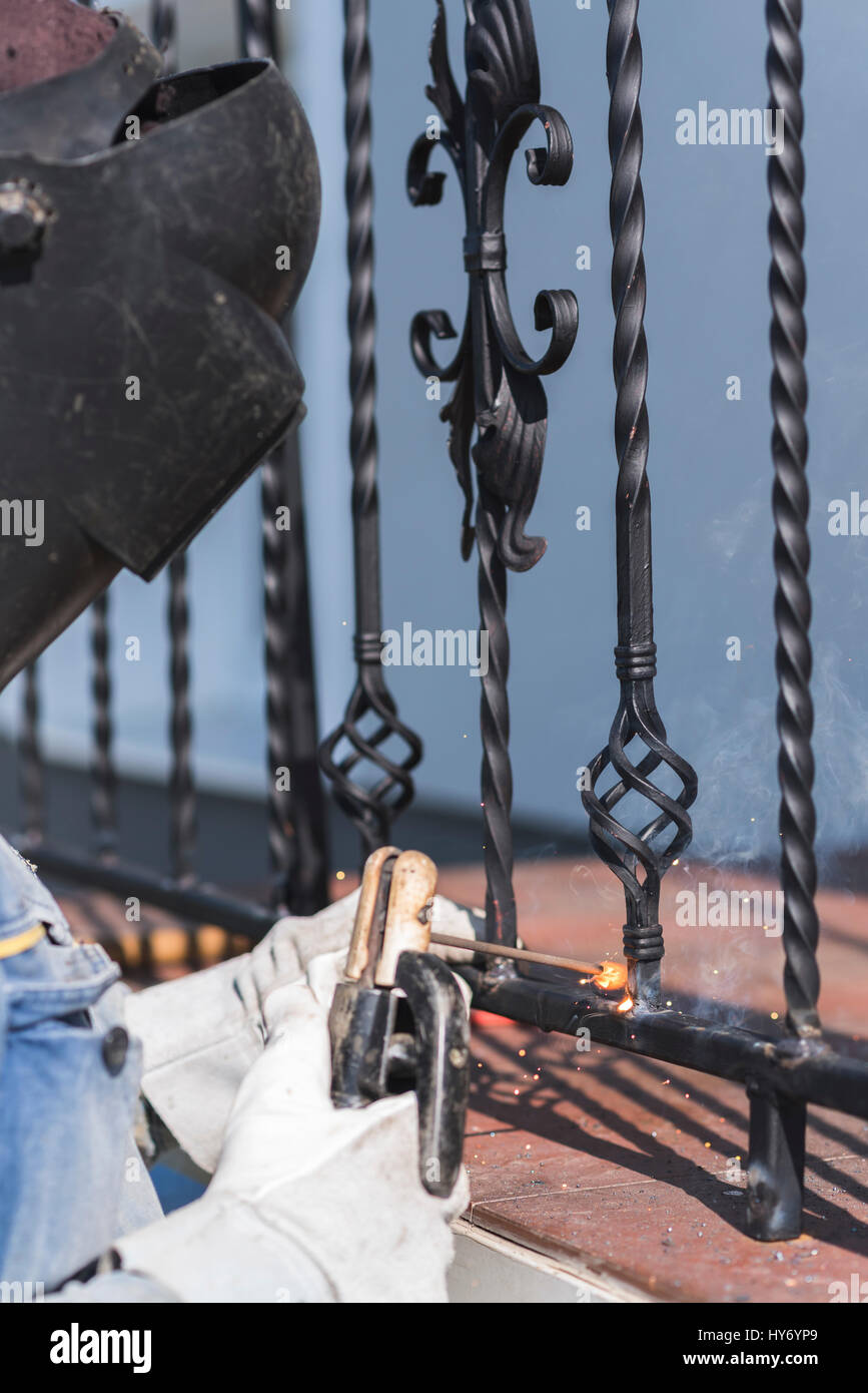 A worker welding metal handrails on the stairs. Wrought iron railings ...
