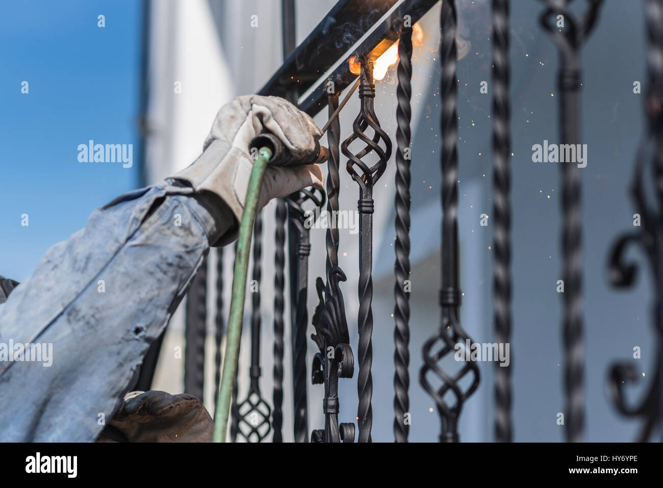A worker welding metal handrails on the stairs. Wrought iron railings ...