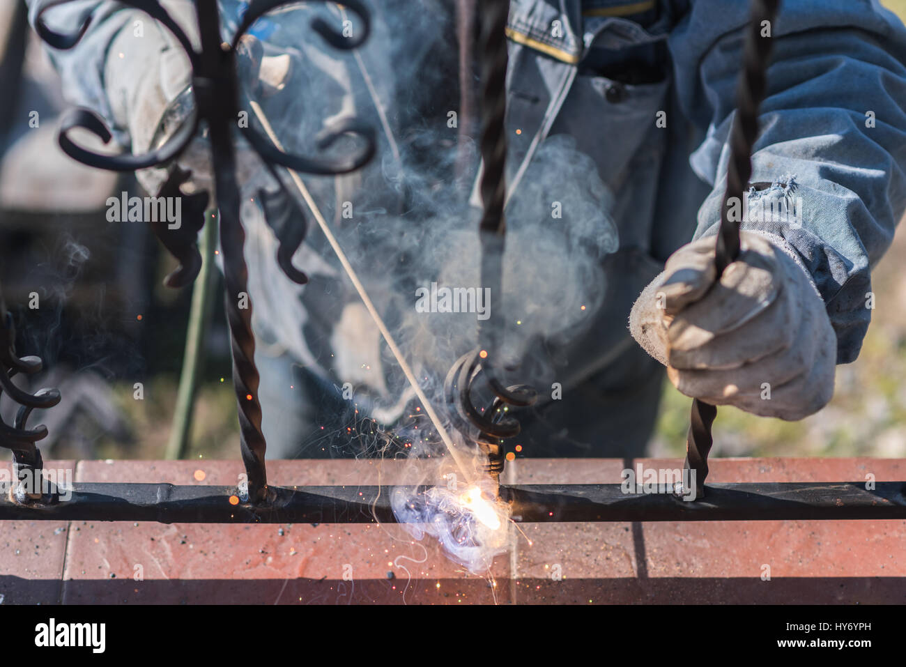 A worker welding metal handrails on the stairs. Wrought iron railings ...