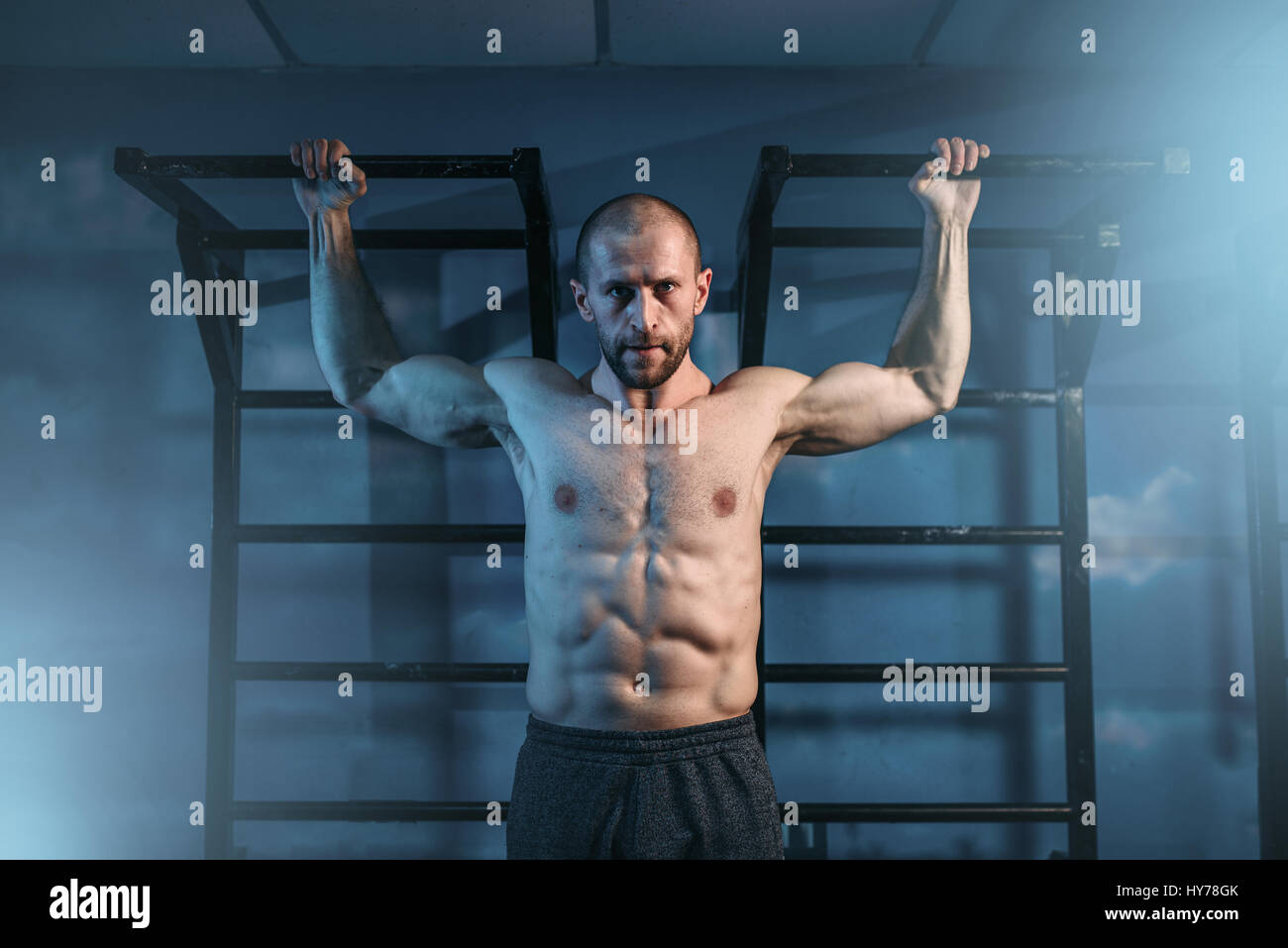 Athlete with muscular body training on horizontal bar in gym. Muscle ...