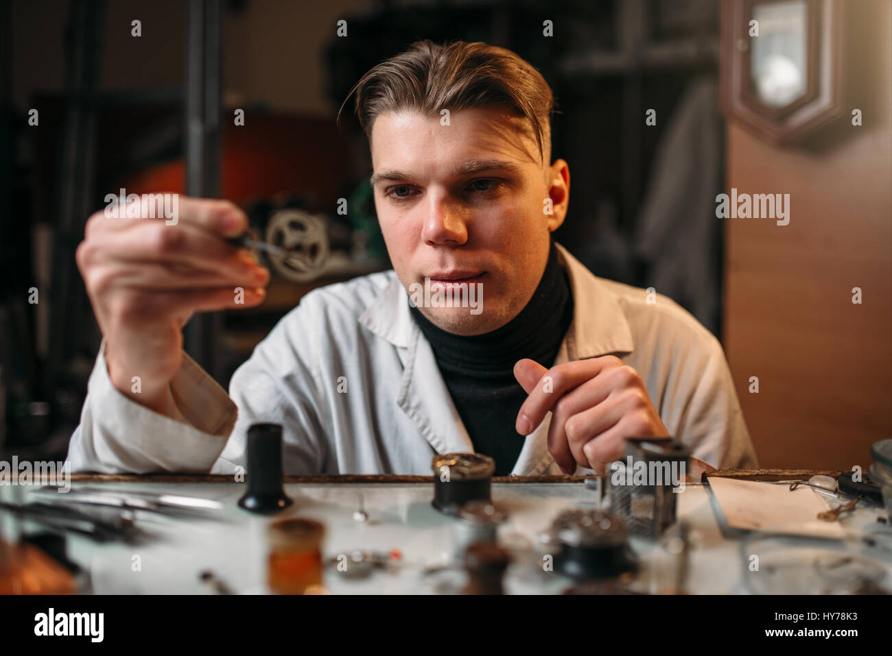 Watchmaker holding with tweezers a gear of old hours. Broken mechanical ...