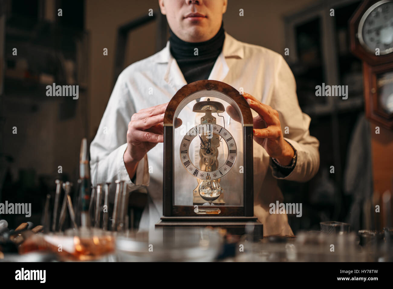 Watchmaker holding old table clock. Antique mechanical watch repairing ...