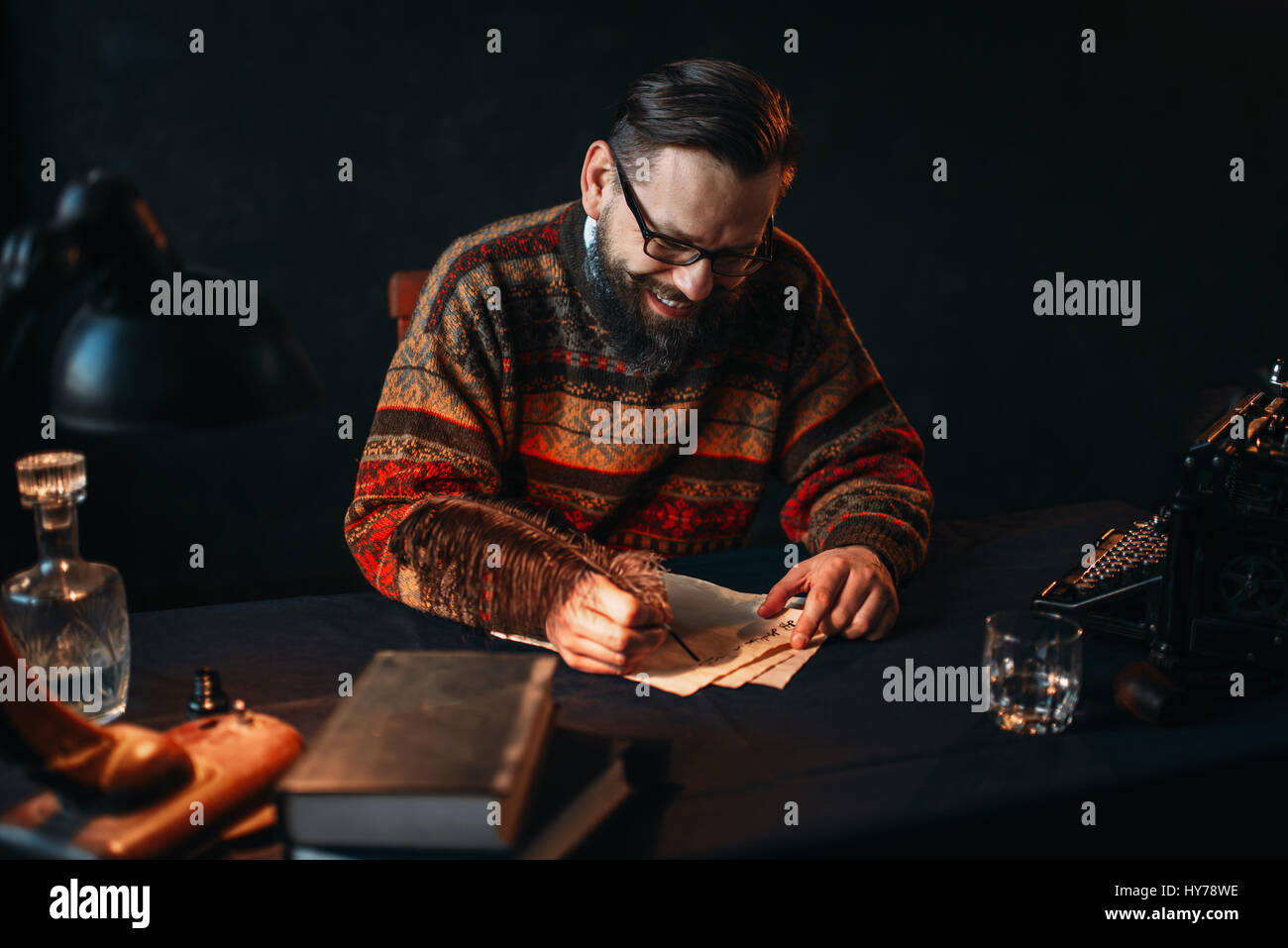 Bearded writer in glasses writes with a feather. Retro typewriter ...