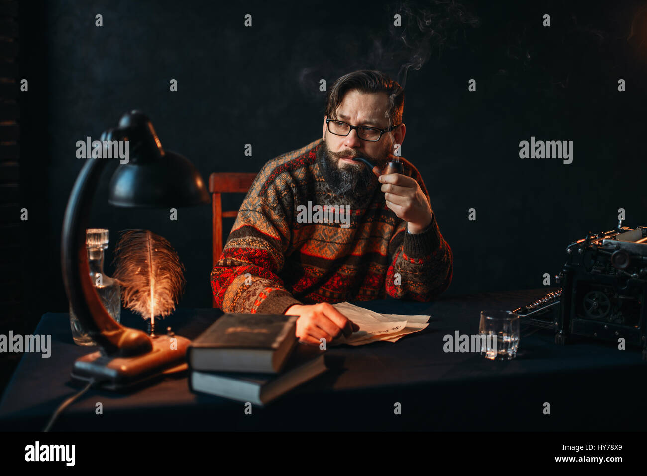 Thoughtful bearded writer in glasses smoking a pipe and look at the ...