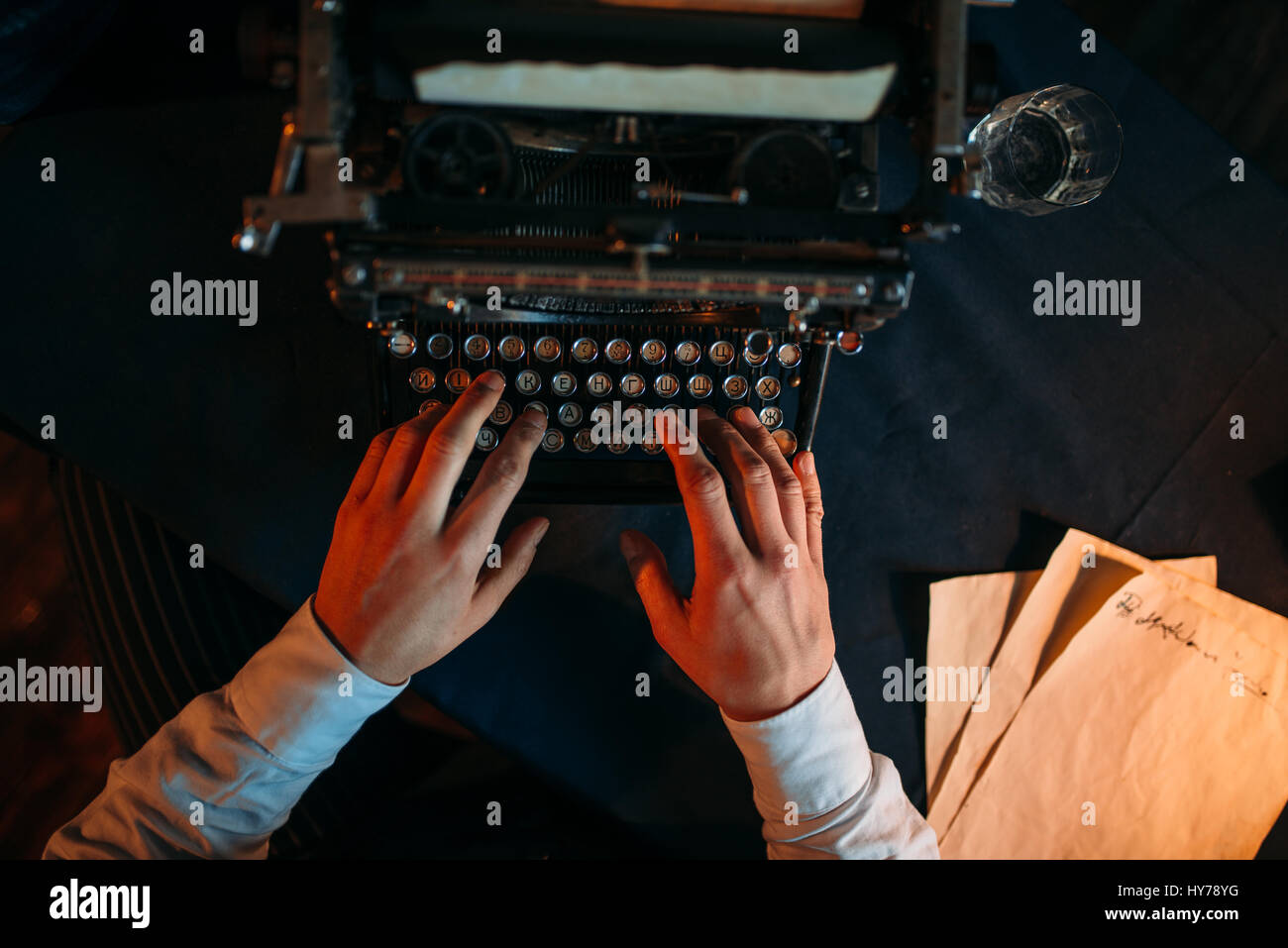 Male hands typing on retro typewriter, top view. Dark blue table cloth ...