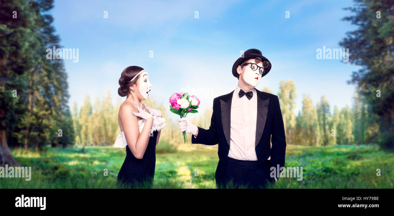 Mime actor and actress performing with flower bouquet, green nature on ...