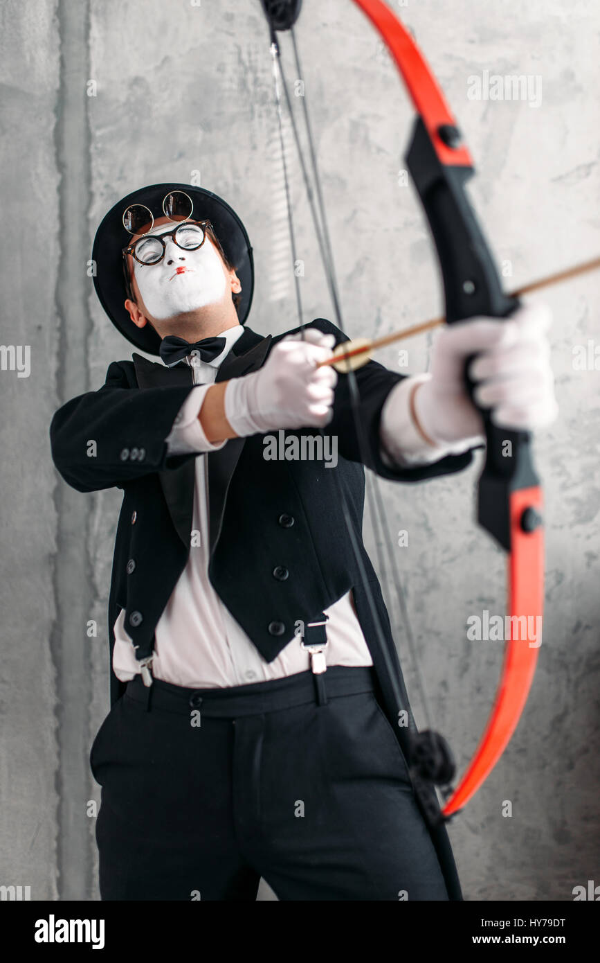 Pantomime actor performing with sports bow. Comedy mime artist in suit ...