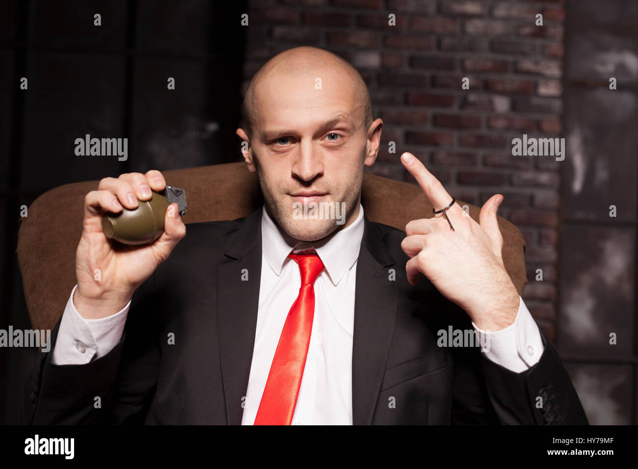 Bald special agent in suit and red tie pulls a grenade pin, dangerous ...