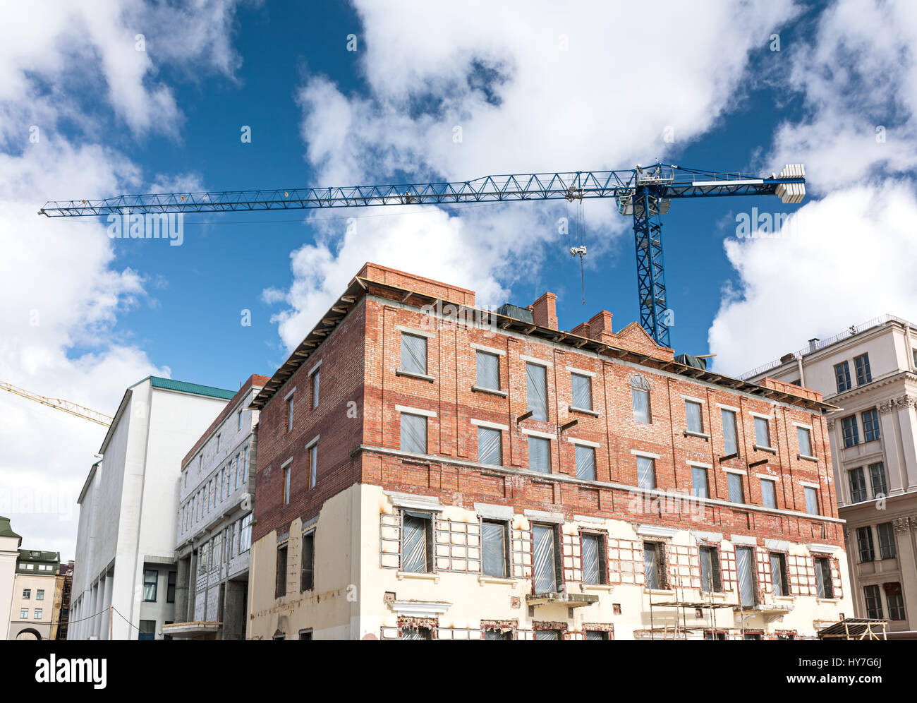 old brick building under reconstruction with building crane on blue sky ...