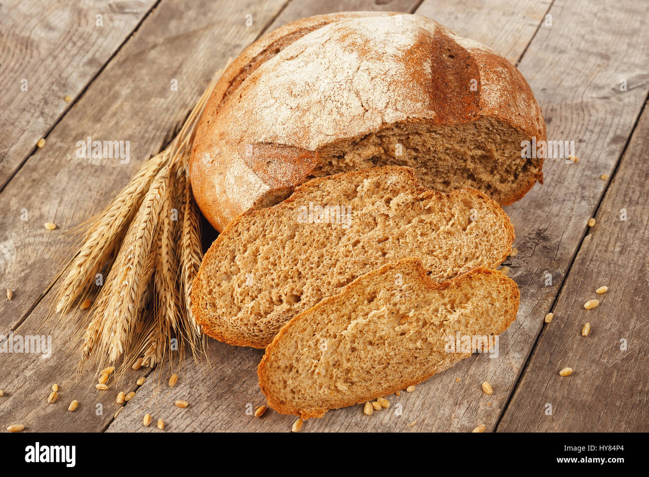 sliced bread with dry cereal ears on a wooden table. Bakery product ...