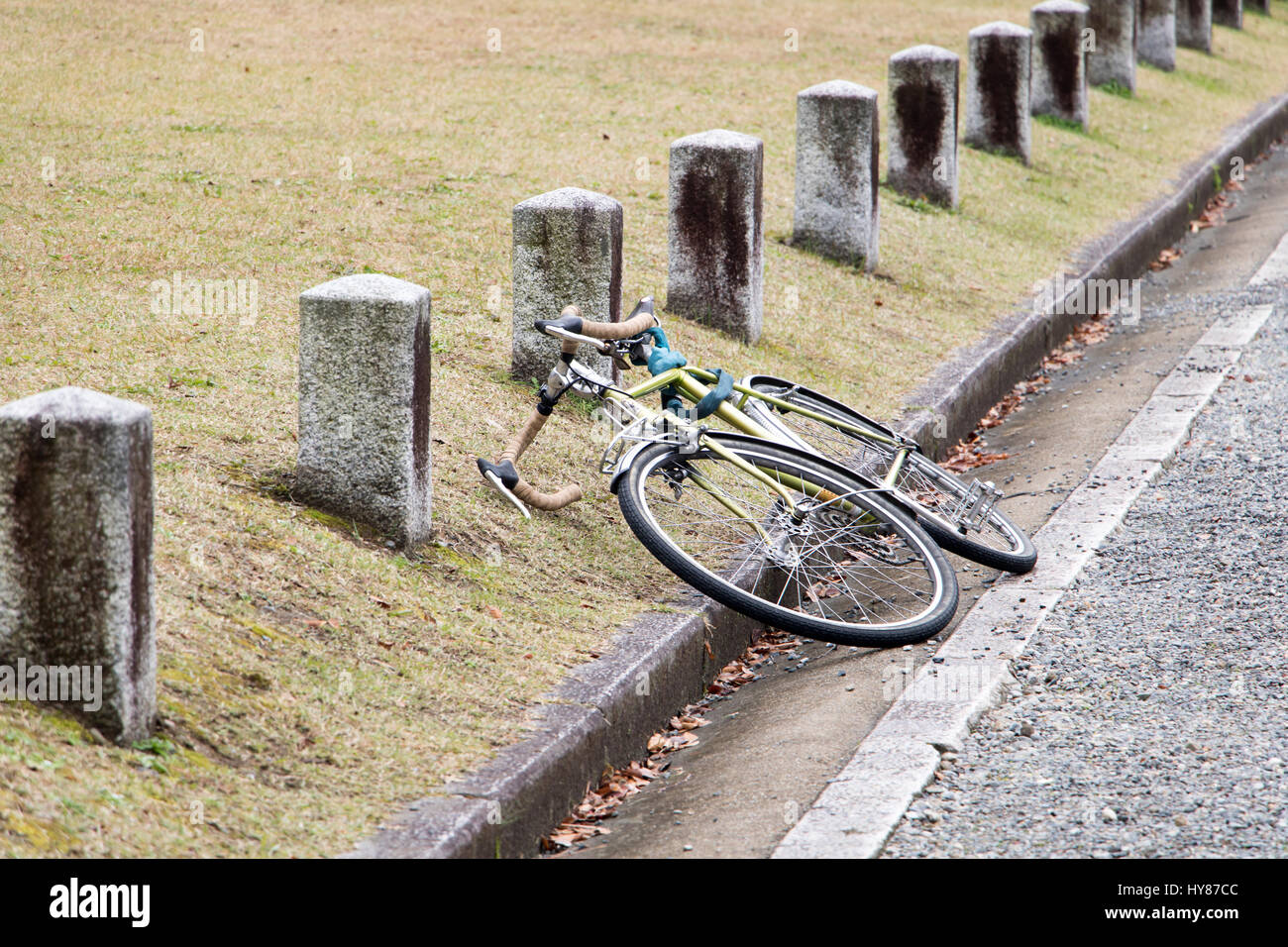 Lying bike on the roadside with bollards. Abandoned bicycle in the park ...